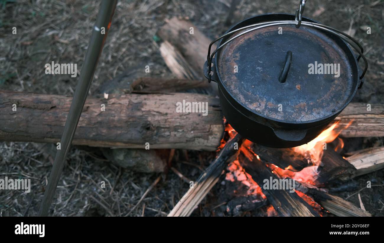 Cooking pot hanging over a campfire on a tripod at a tourist camp, a ...