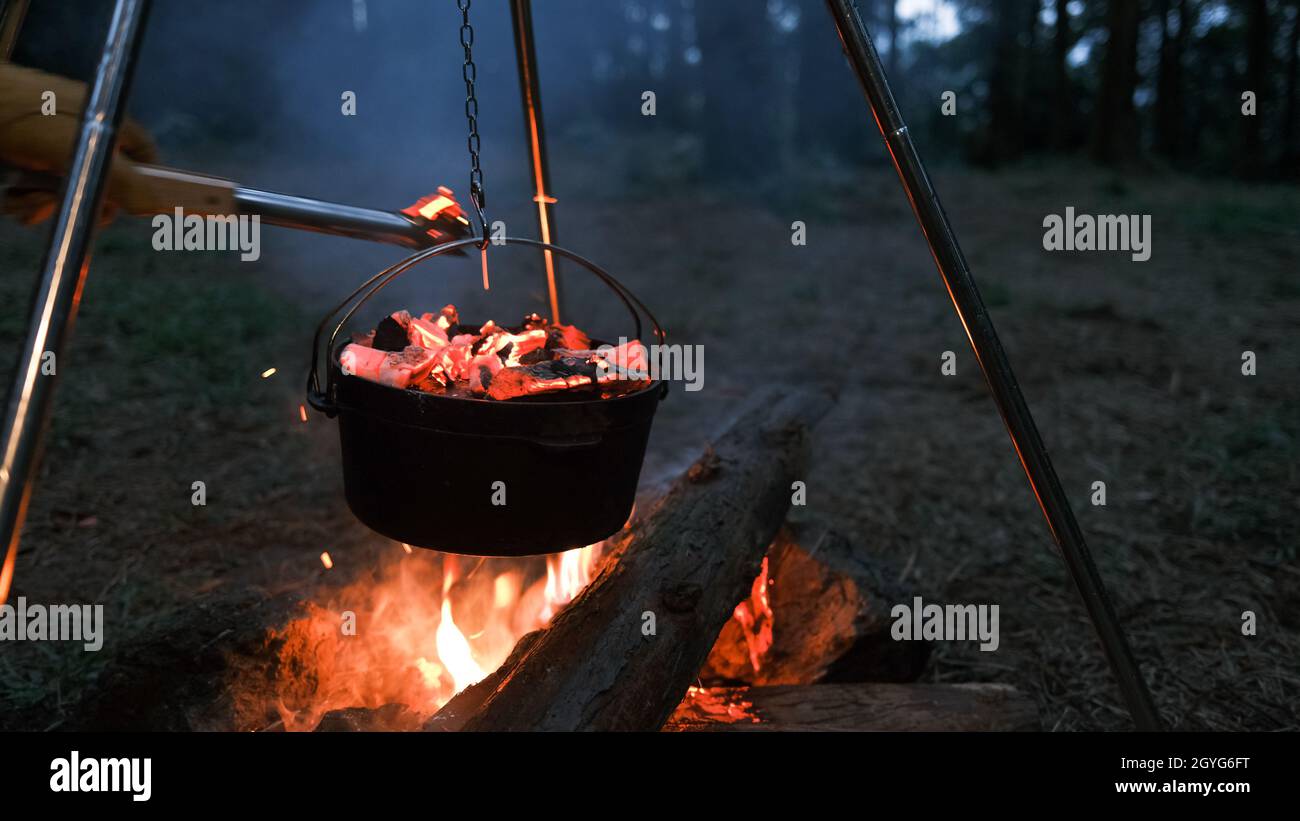 Cooking pot hanging over a campfire on a tripod at a tourist camp, a ...