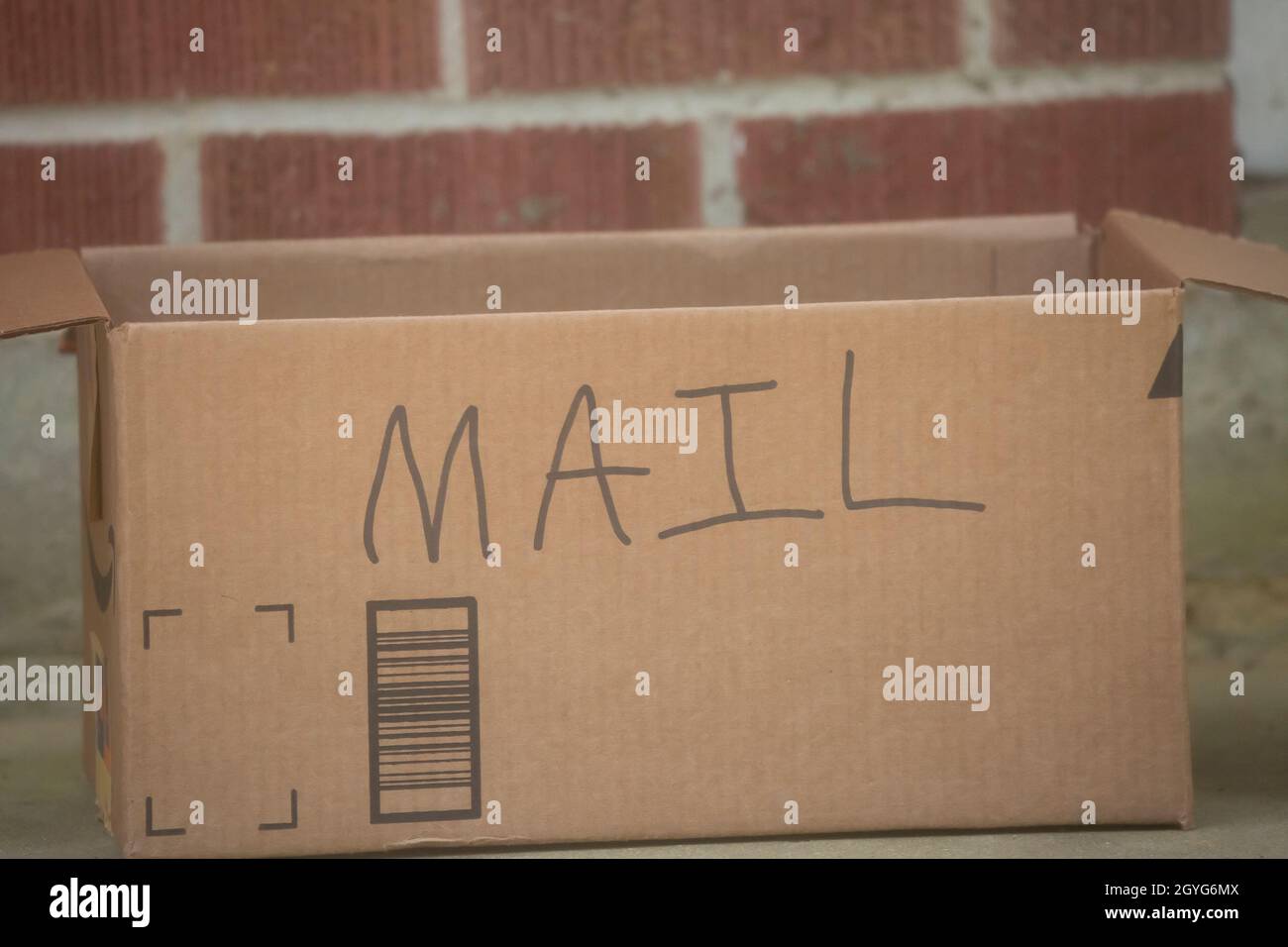 Cardboard box with the word MAIL written on it in front of a red brick ...
