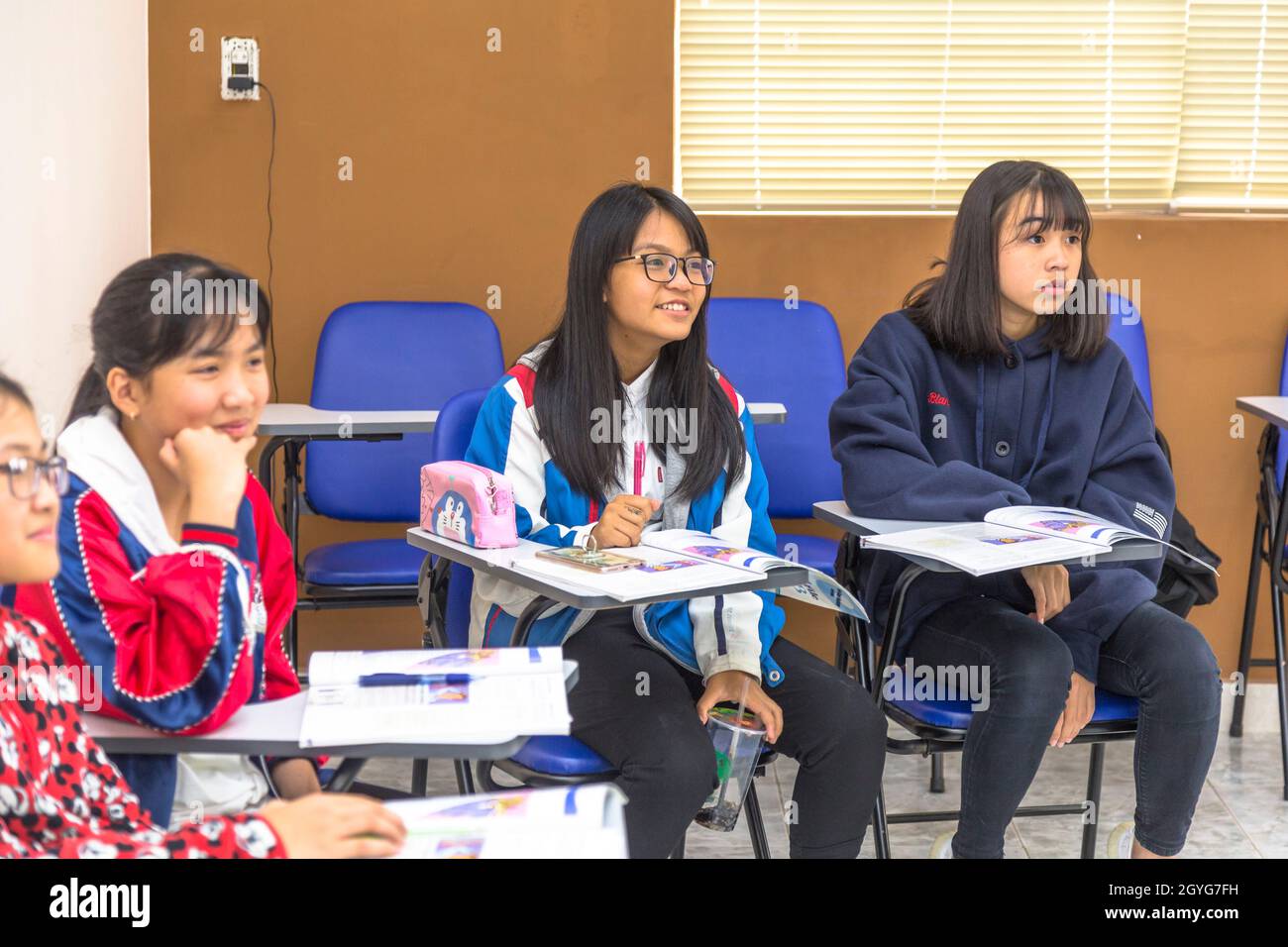 Three female students listening in class Stock Photo - Alamy