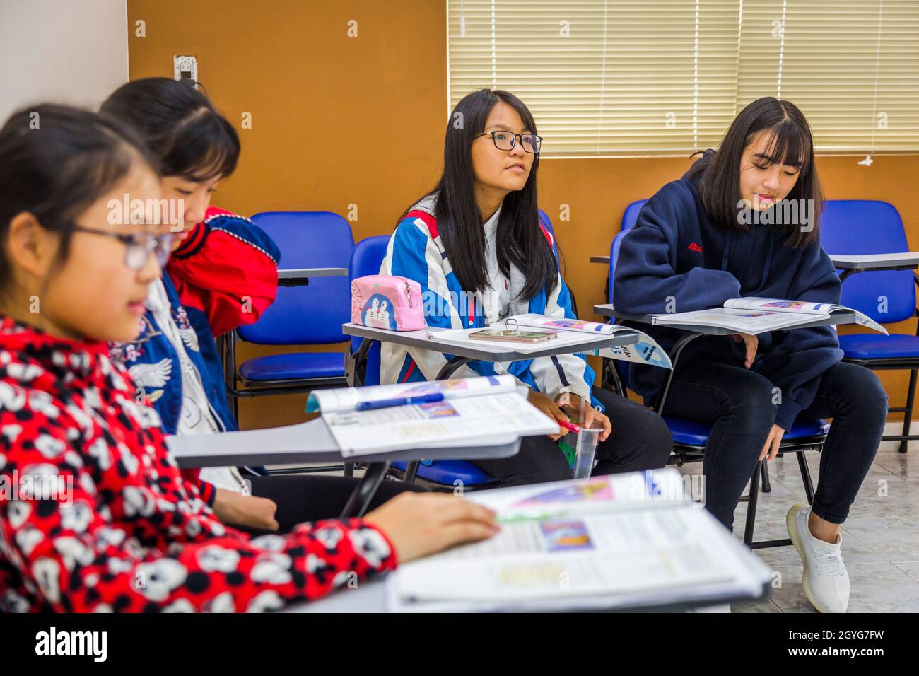 Four young female Vietnamese asian students at their desk in class ...