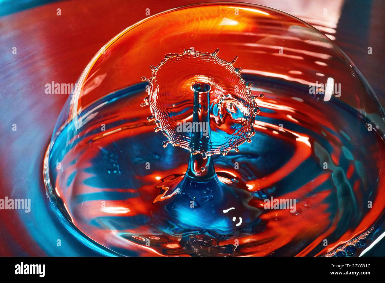 Two water drops meeting in air inside bubble on blue and red water ...