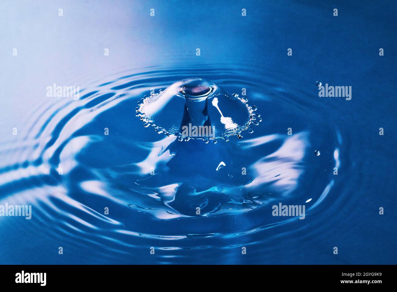 Clean blue water broken by ripples from two water drops hitting in air ...