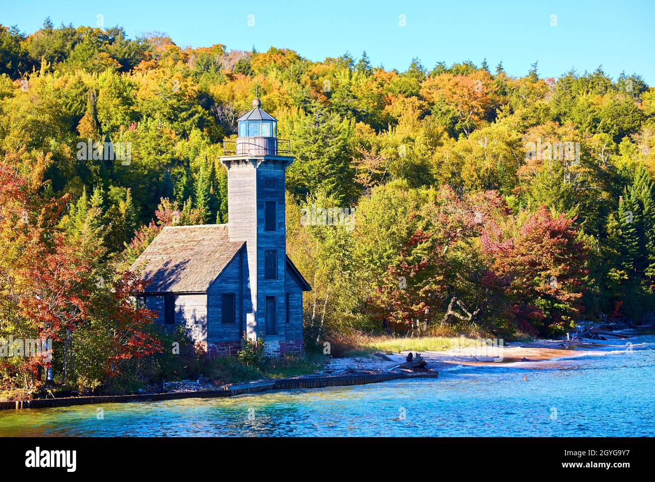 Wooden lighthouse at edge of forest with tiny water barrier Stock Photo ...