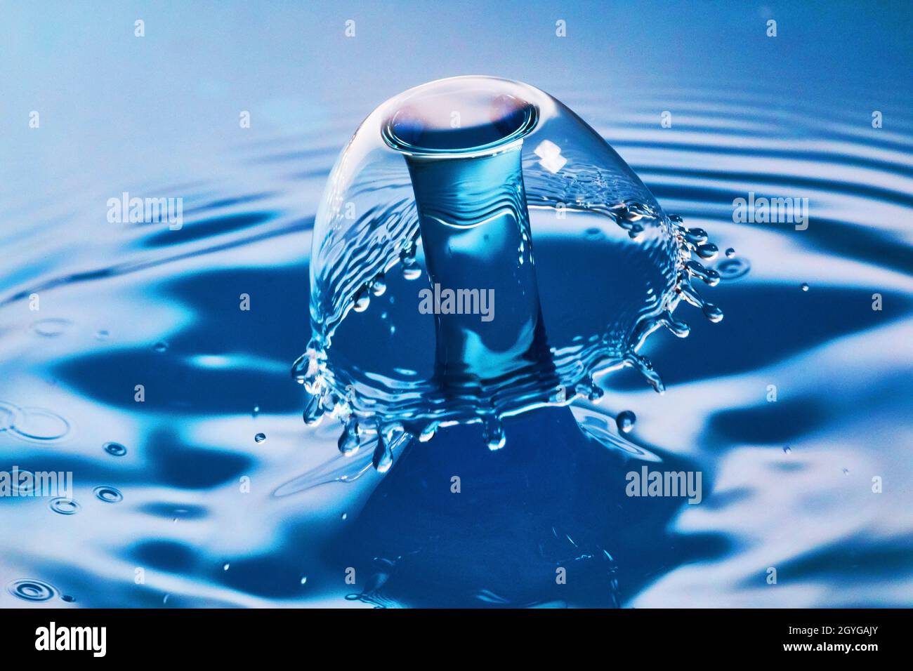Collision of two water drops on blue water with ripples Stock Photo - Alamy