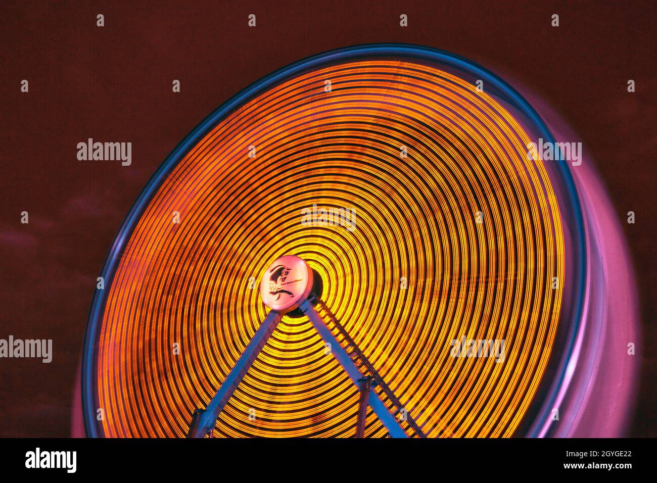 Yellow spinning ferris wheel at night in infrared at a carnival or fair ...