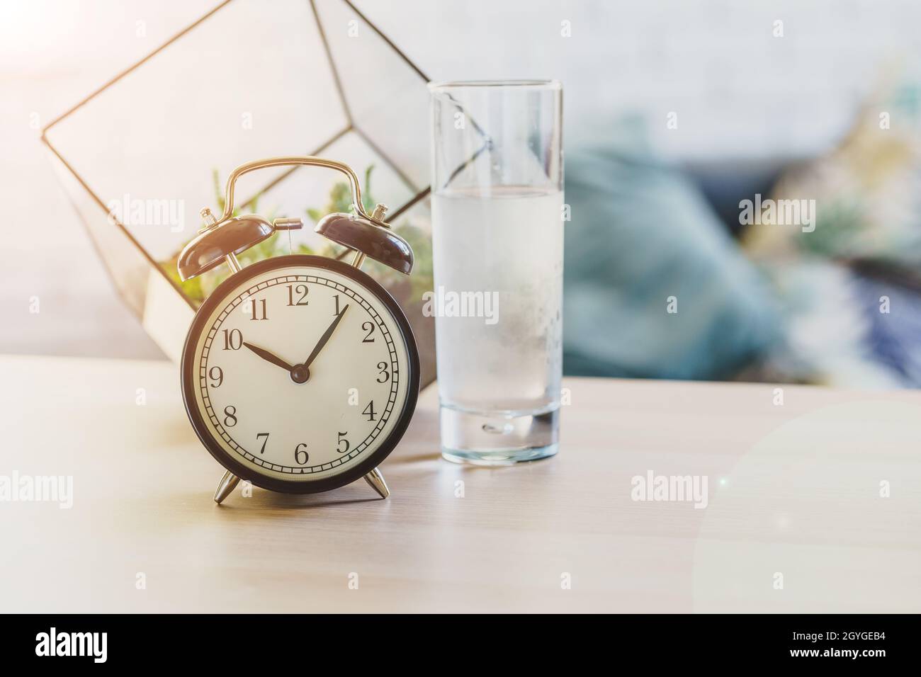 Drinking water health concept. Alarm clock and glass of water on table ...