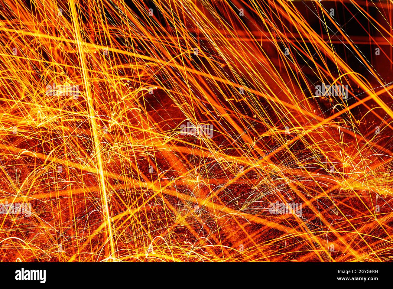Orange and yellow sparks against a pavement ground at night Stock Photo ...