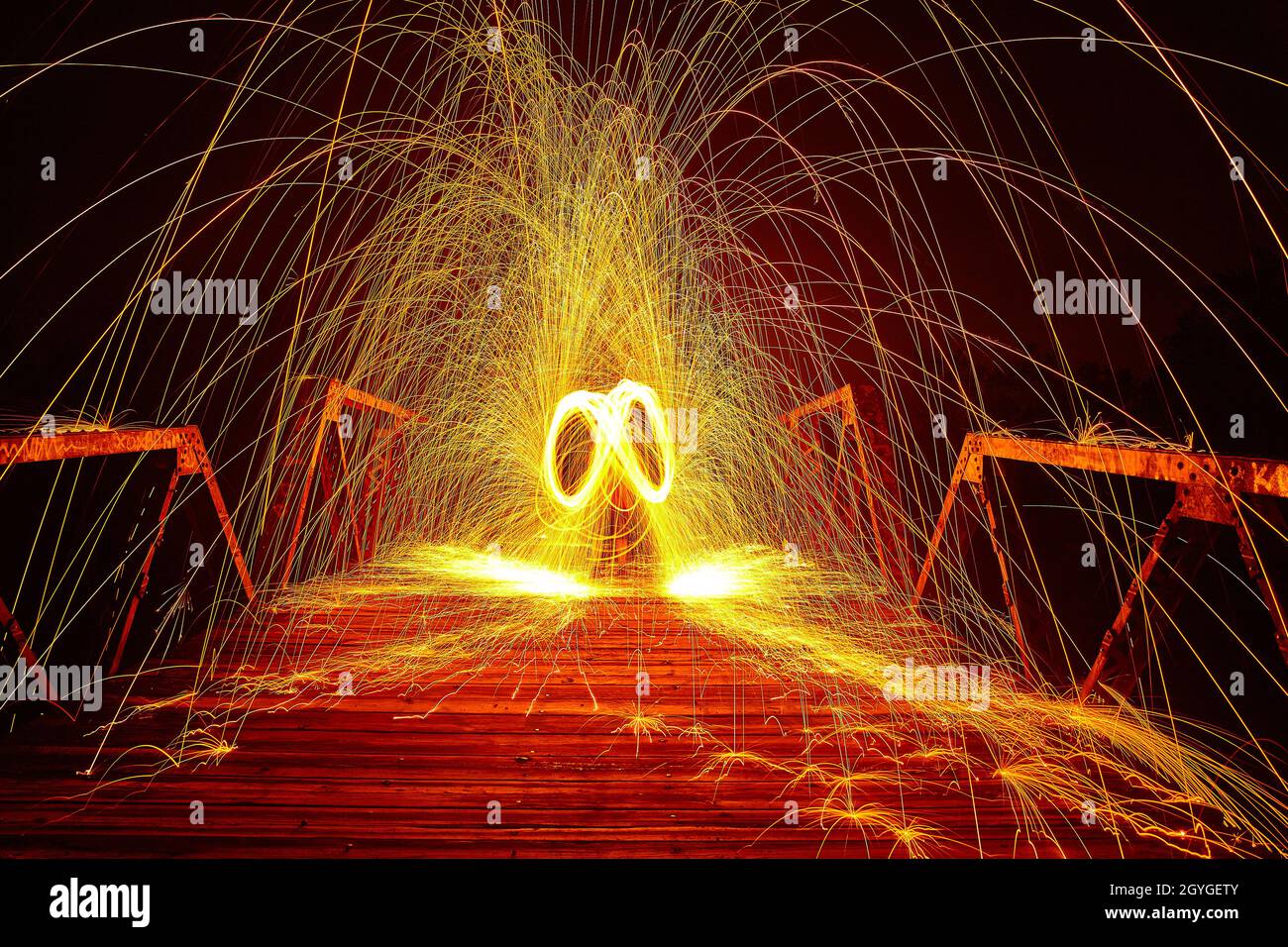A single infinity symbol made of yellow sparks at night on a bridge ...