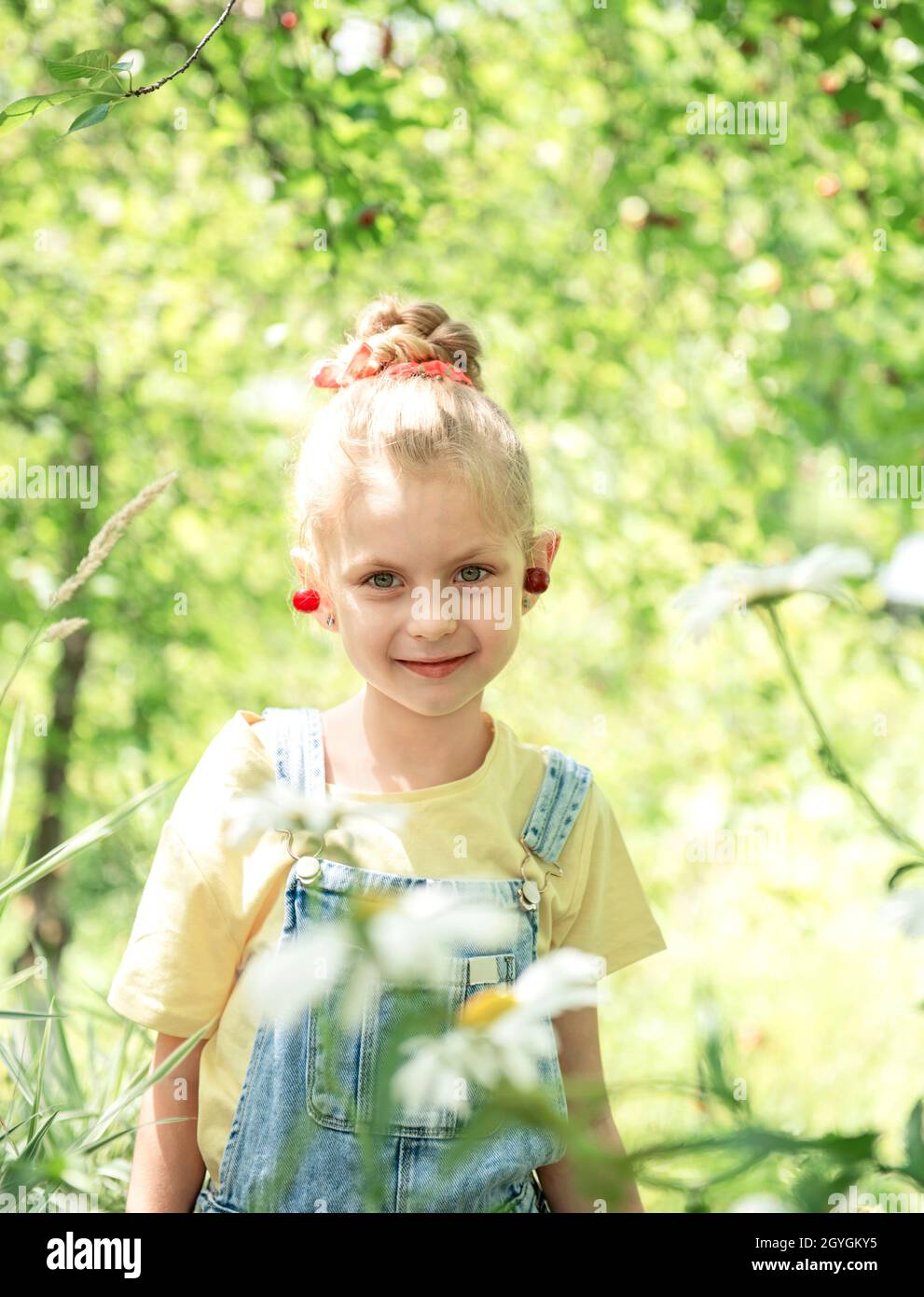 Cute little girl picks a cherry from a tree in cherry garden Stock ...