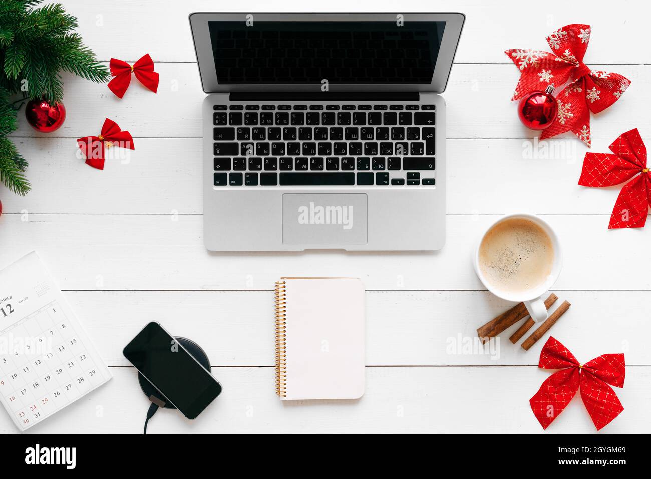 Laptop on white wooden desk surrounded with red Christmas decorations ...