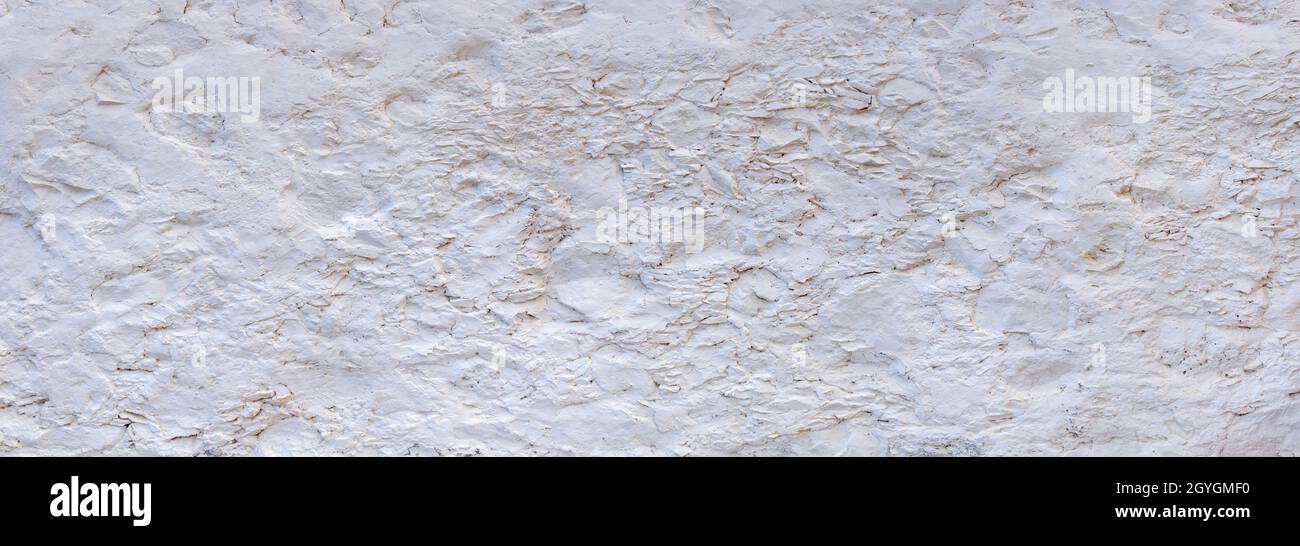 Very rough, white painted wall made of rubble stones in close-up Stock ...