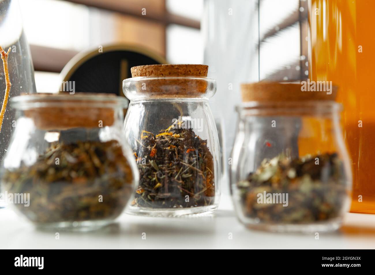 Glass jars with dry tea leaves close up on white table Stock Photo - Alamy