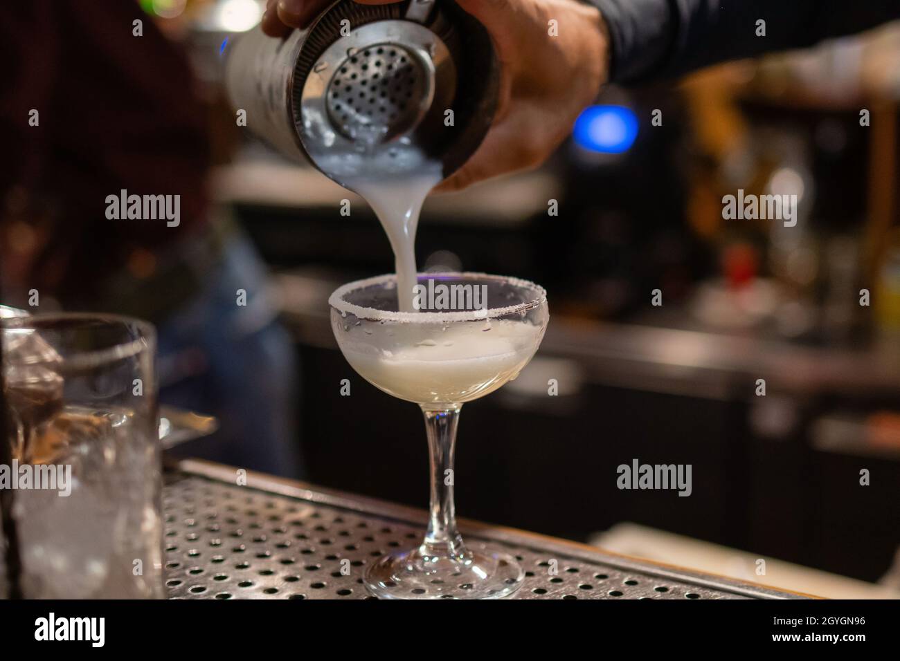 The bartender makes a cocktail at the bar, pours a glass of the shaker ...