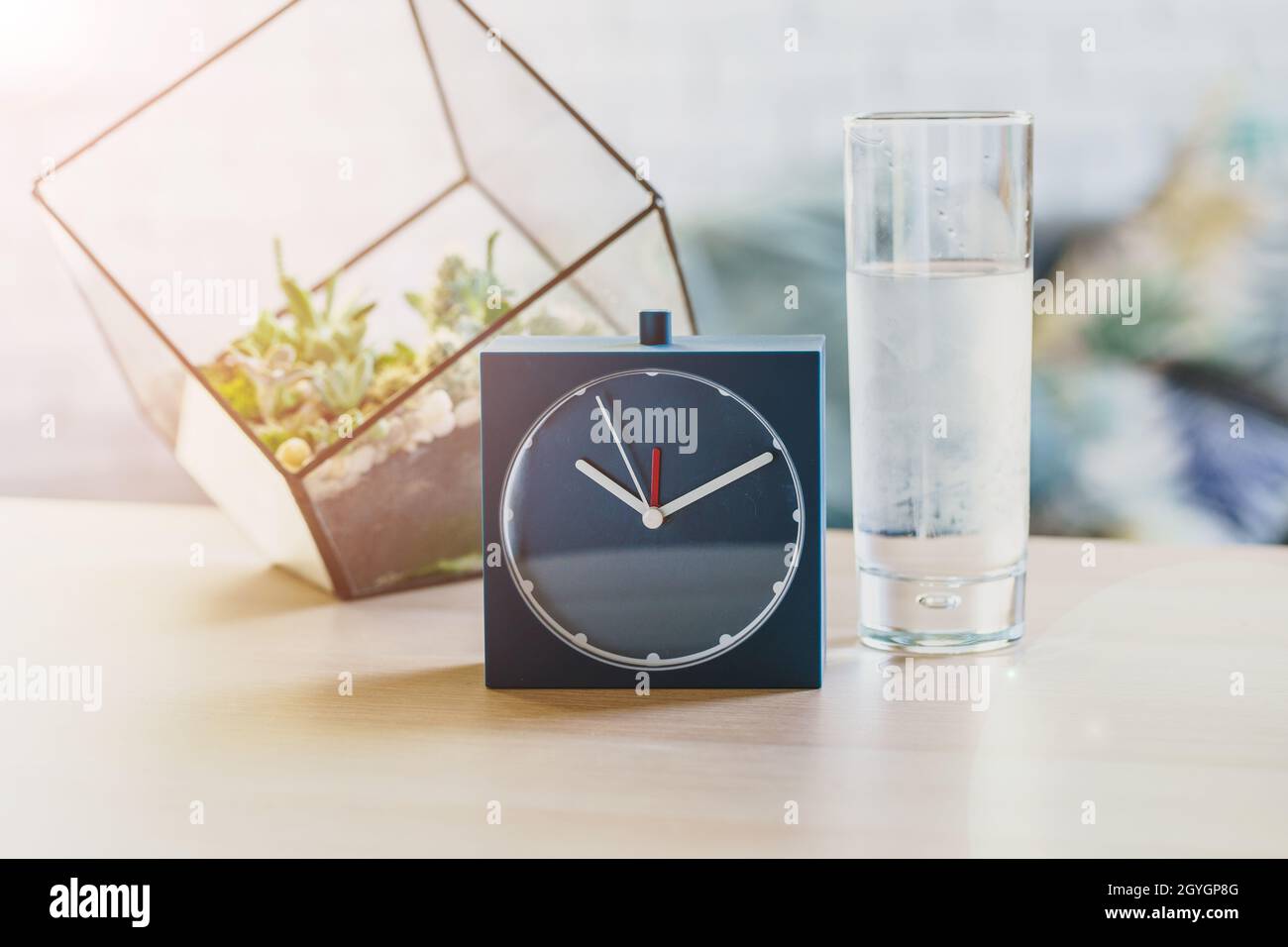 Drinking water health concept. Alarm clock and glass of water on table ...