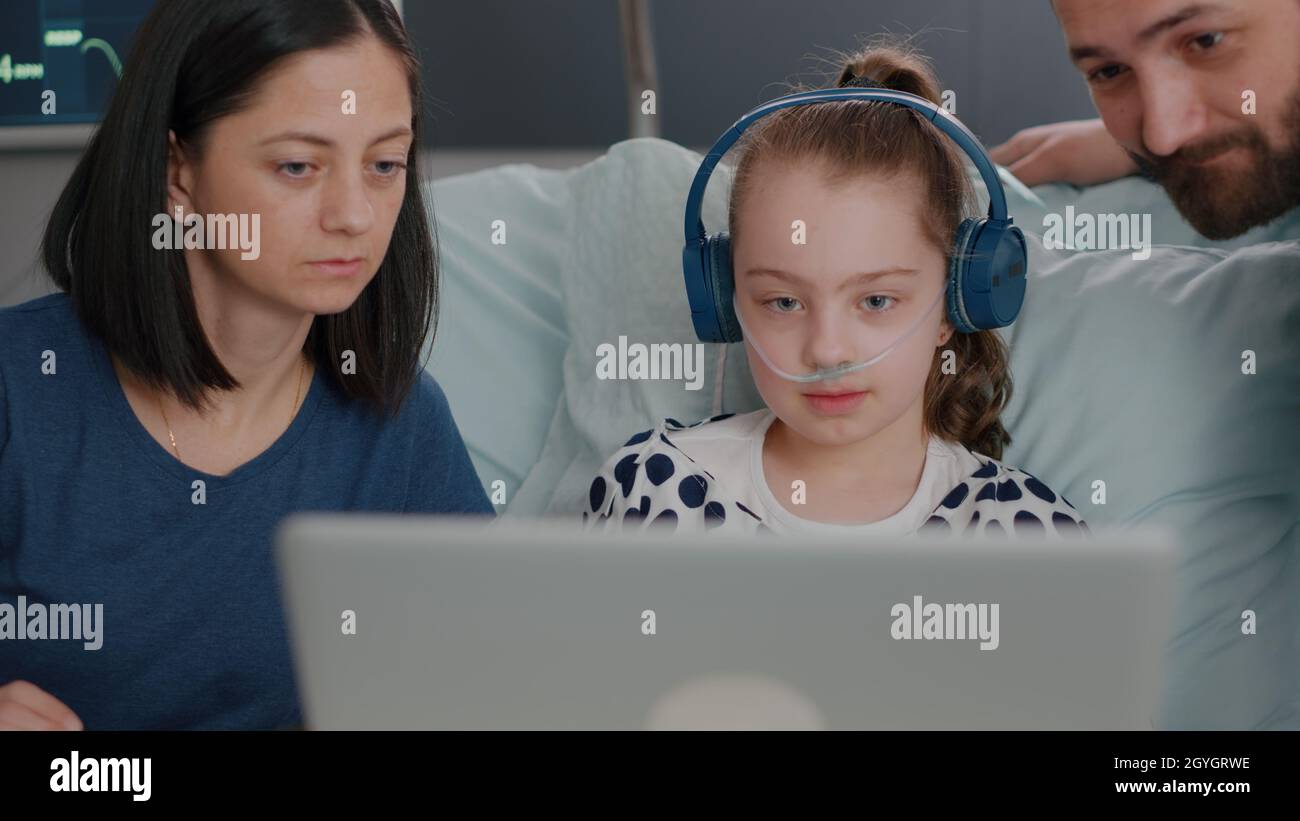 Family sitting beside daughter while playing online videogames using ...