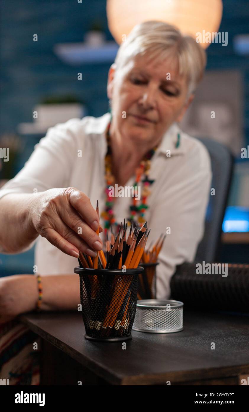 Close up of elder artist using pencils on table at studio. Senior ...