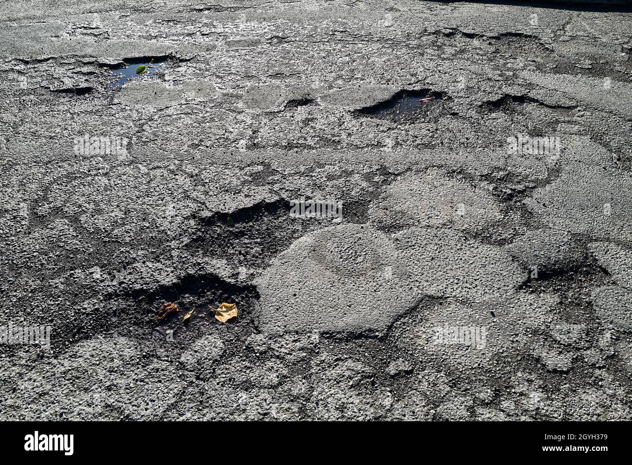 Broken and damaged tarmac surface on a road Stock Photo - Alamy