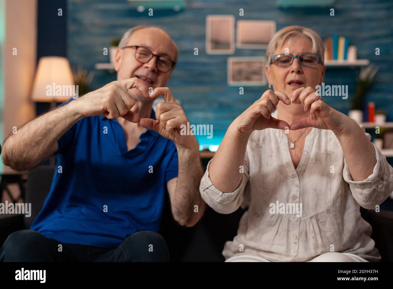 Married aged couple doing heart symbol with hands while looking at ...