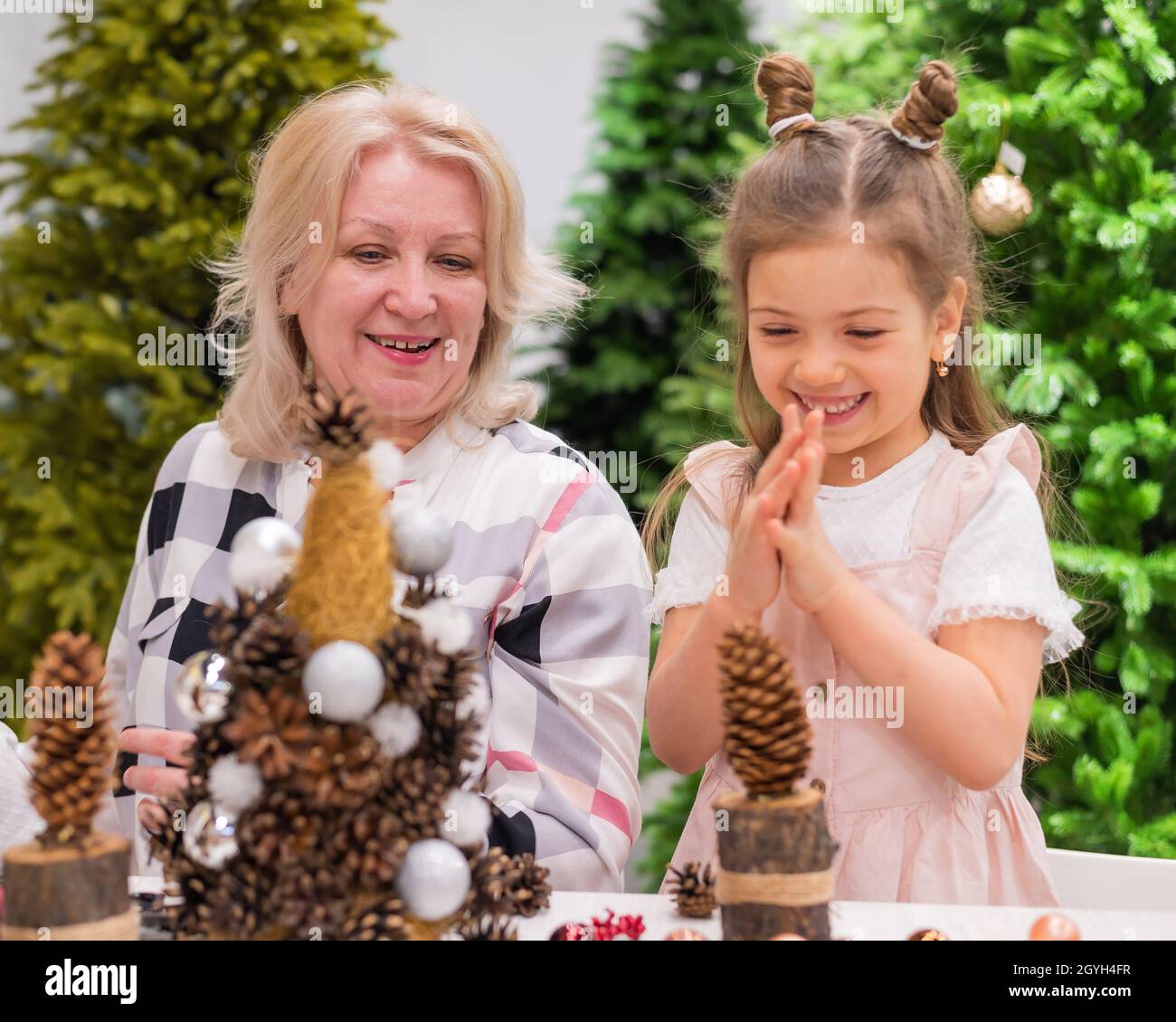 Elderly caucasian woman making pine cones decoration for christmas with ...