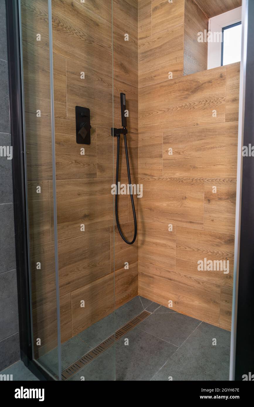 Corner view of a modern shower cubicle with woodgrain pattern tiles and ...