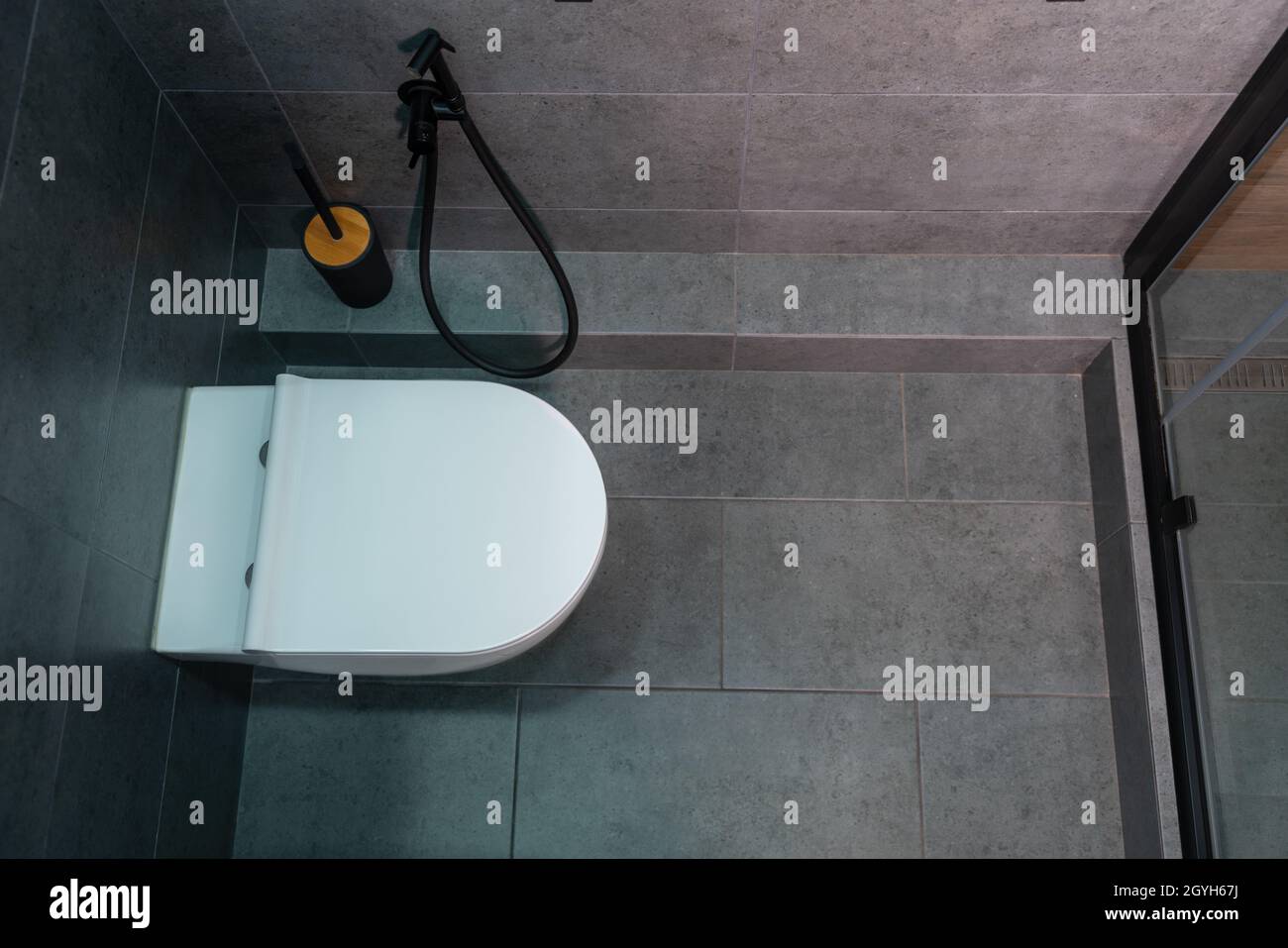 Looking down upon the closed seat of a wall-mounted toilet in a modern ...
