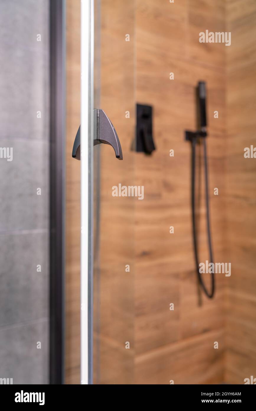 Open glass door to a modern wood effect shower cubicle in a home or ...