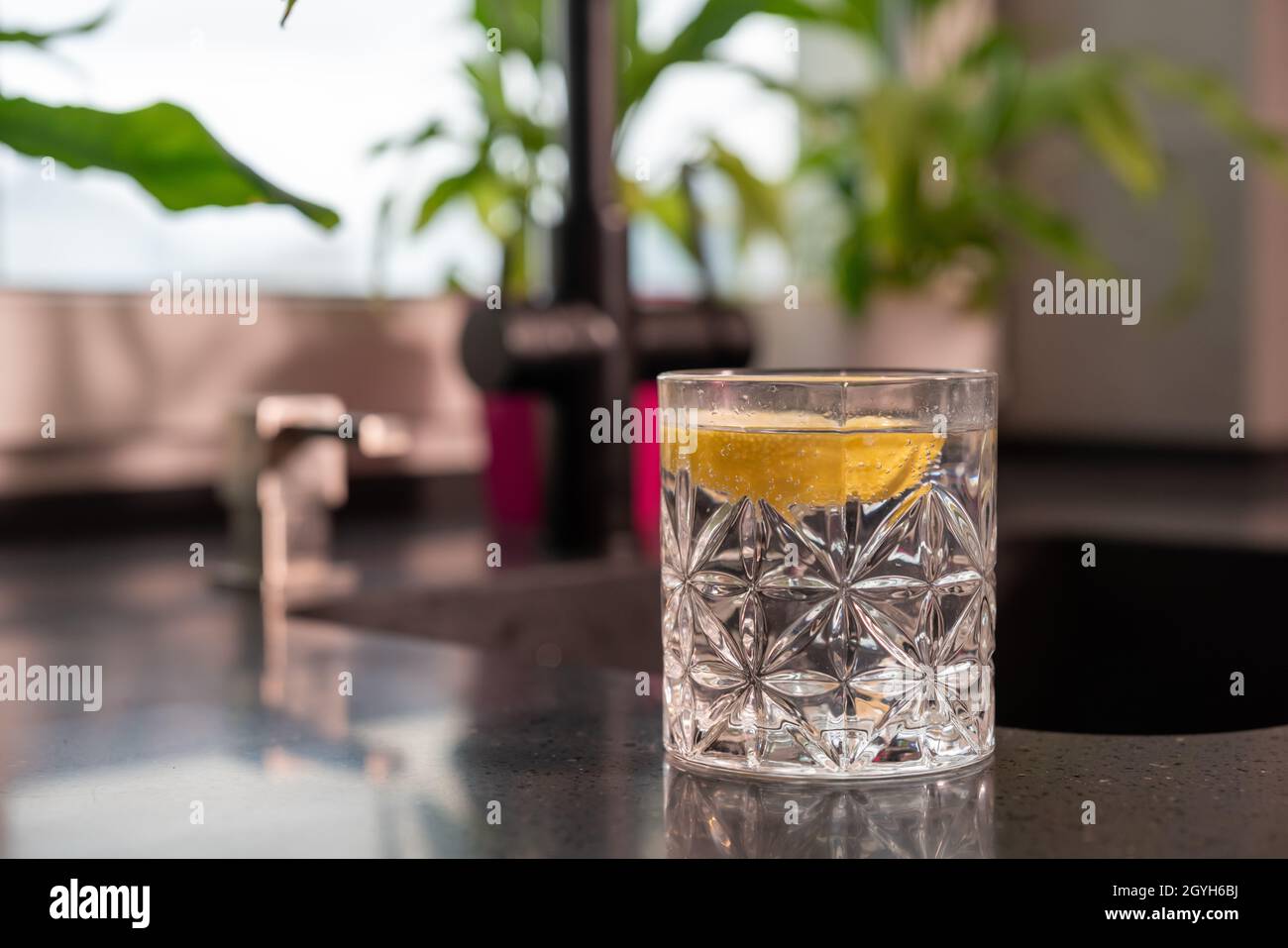 Glass of healthy pure fresh water with tangy lemon on a countertop in a ...