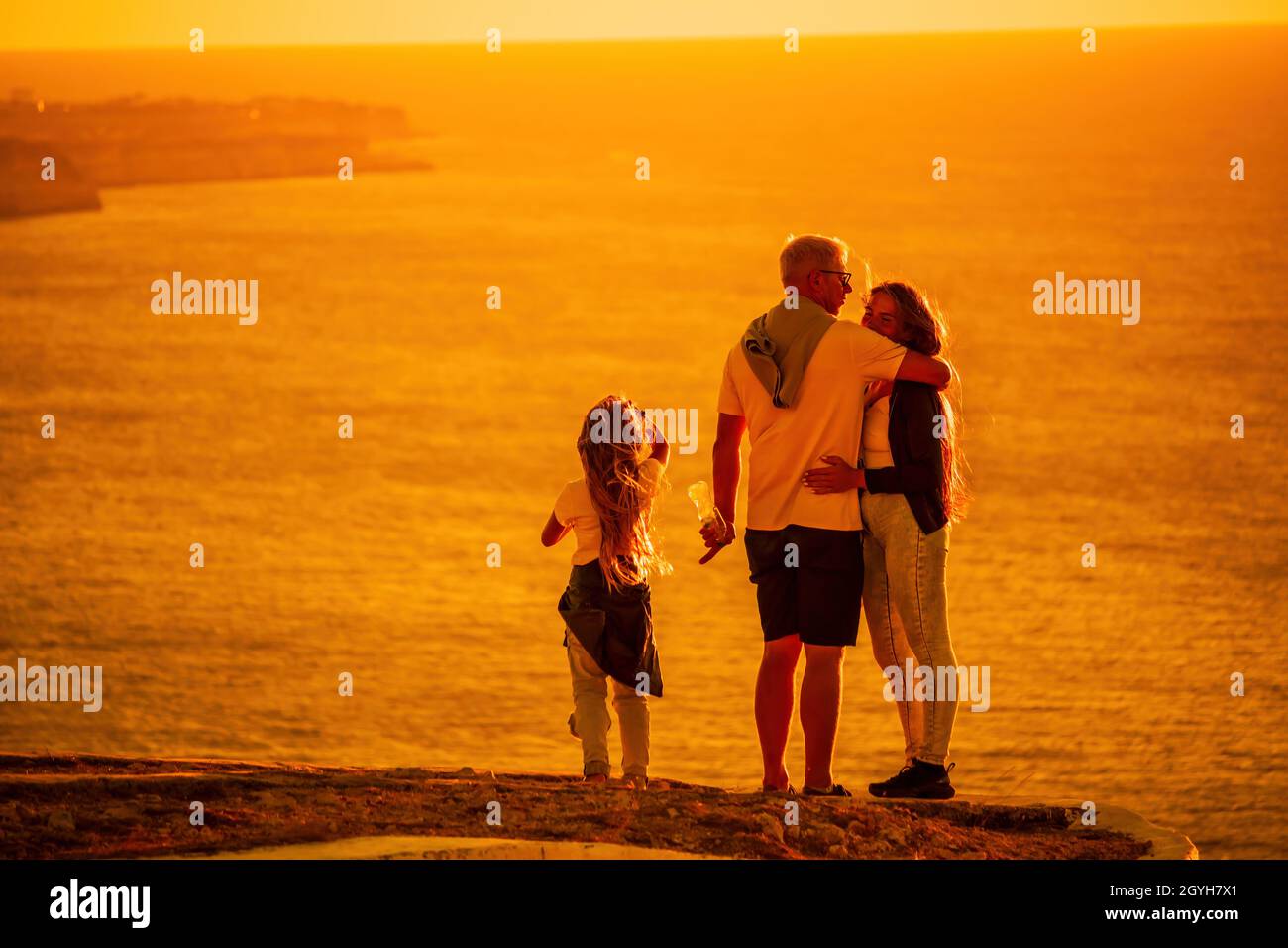 Silhouette of a young romantic couple with a child enjoying the evening ...
