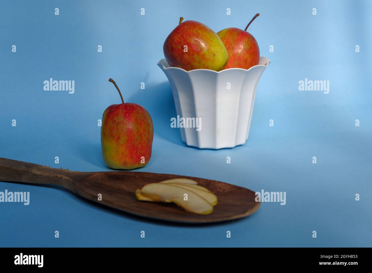 Few green red apples and a wooden spoon with sliced apples on a blue ...