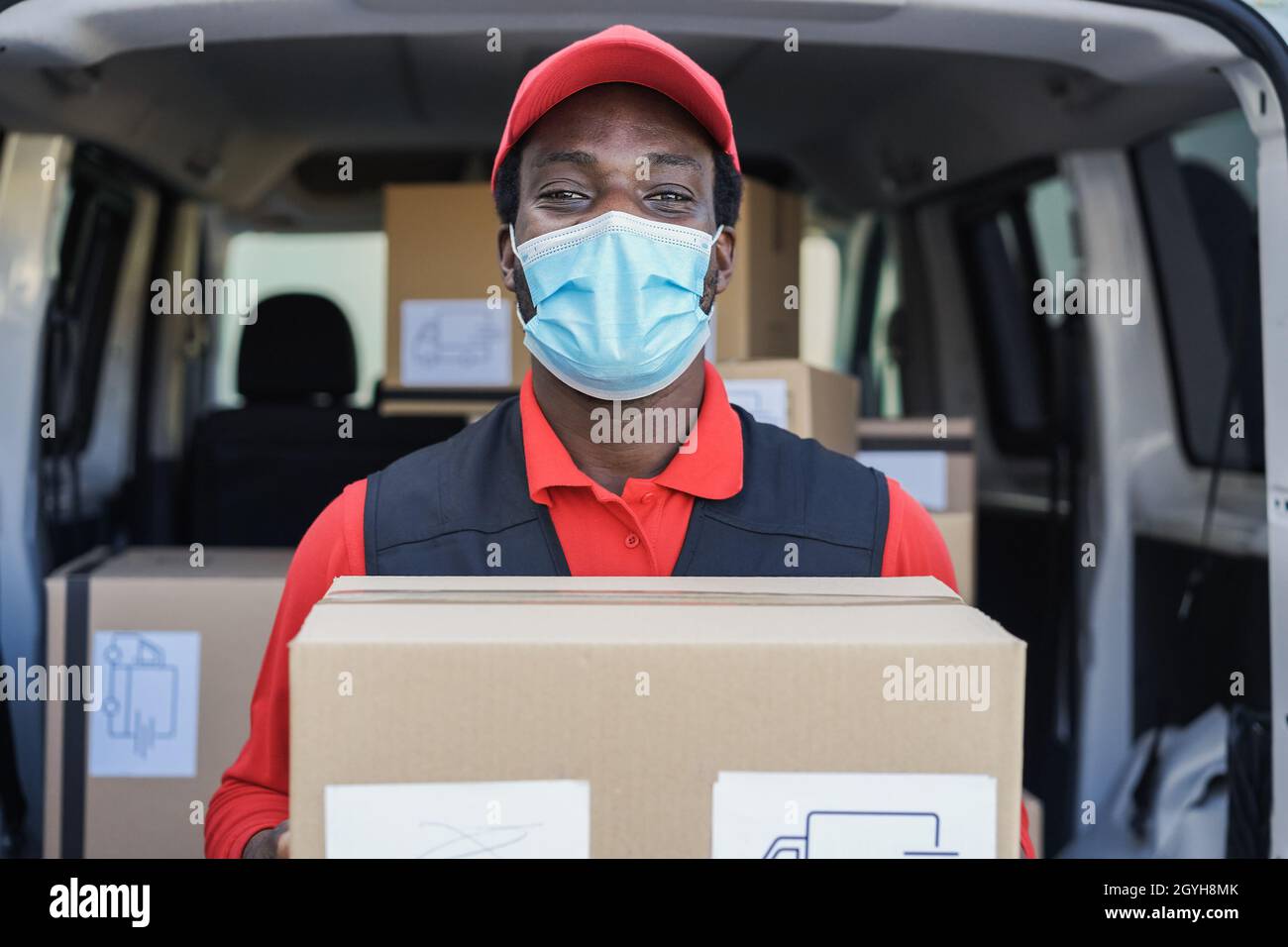 Black courier man delivering package in front of cargo truck wearing ...