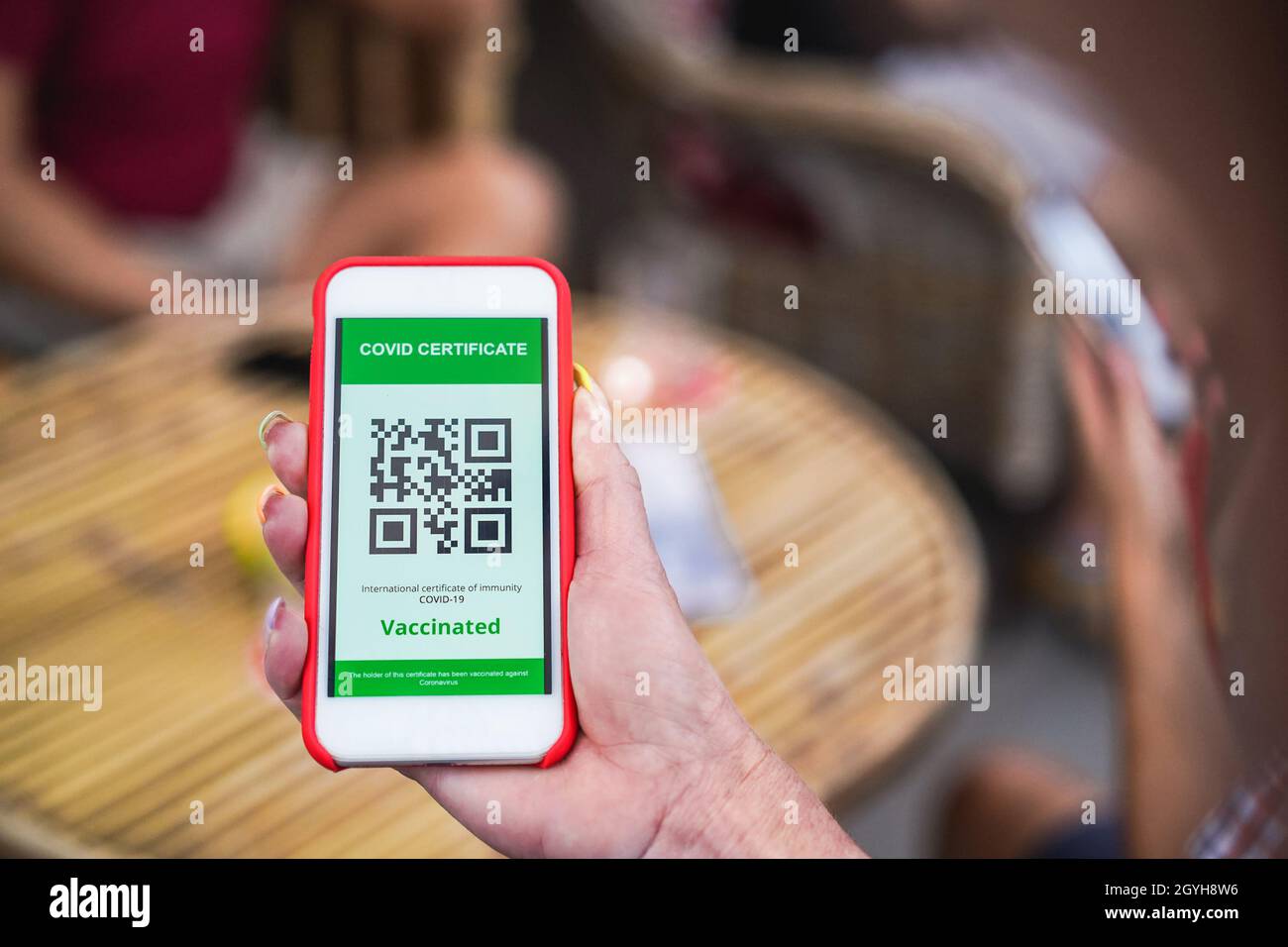 Woman holding mobile phone with covid QR code certificate in front of ...
