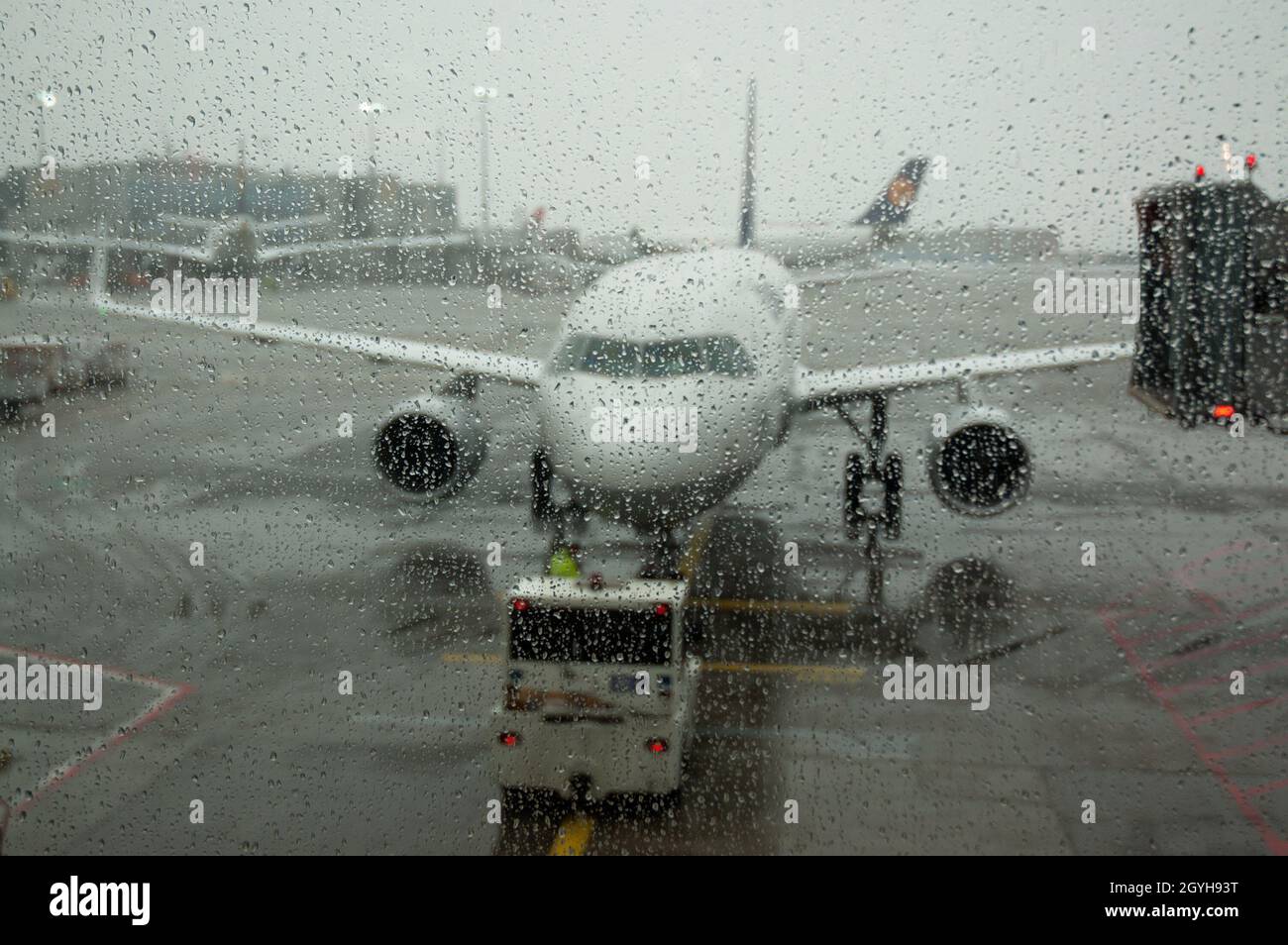 Airplane on runway seen through wet window on rainy day - Focus on the ...