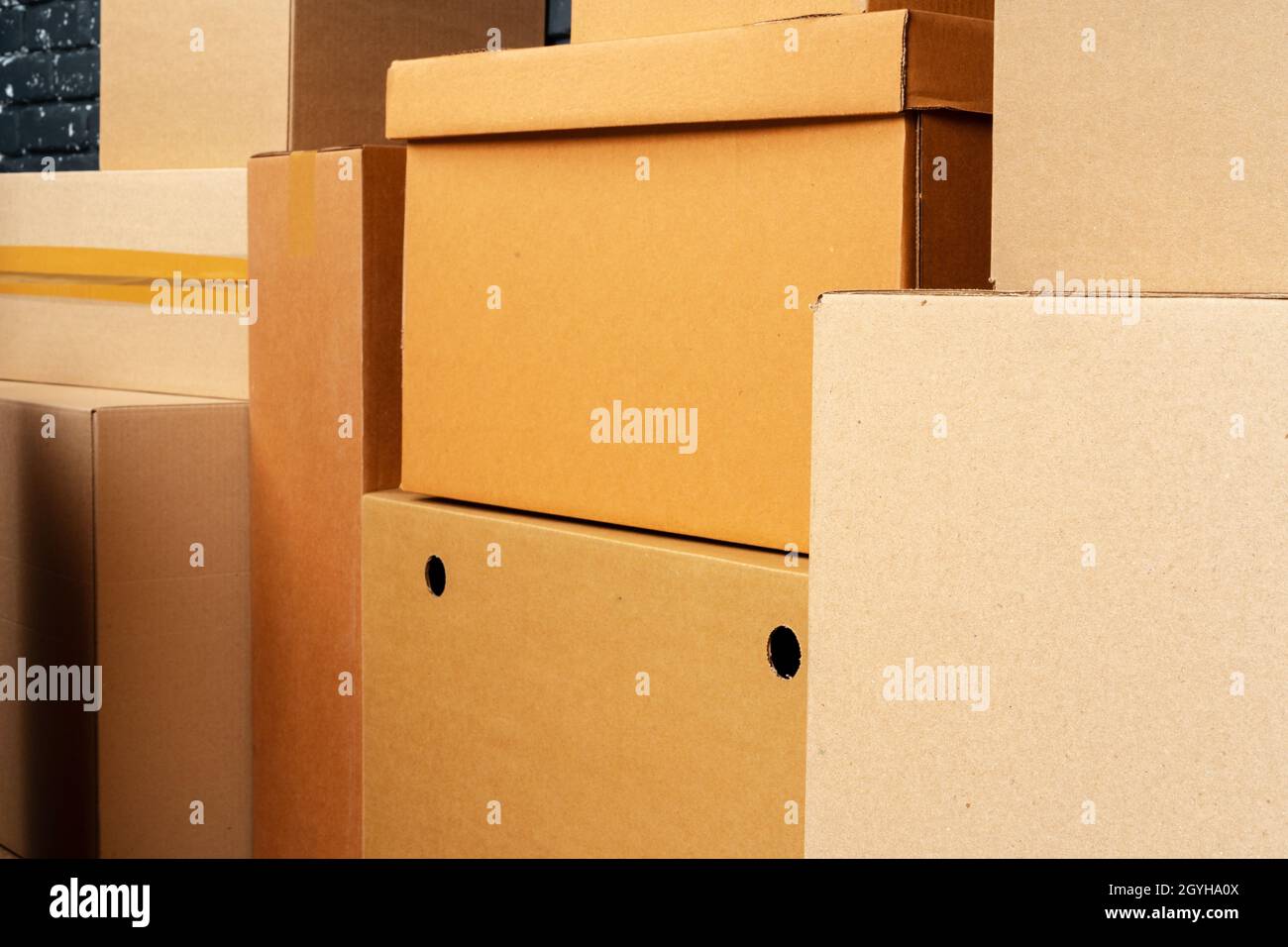 Stack of cardboard boxes in the empty room against black brick wall ...