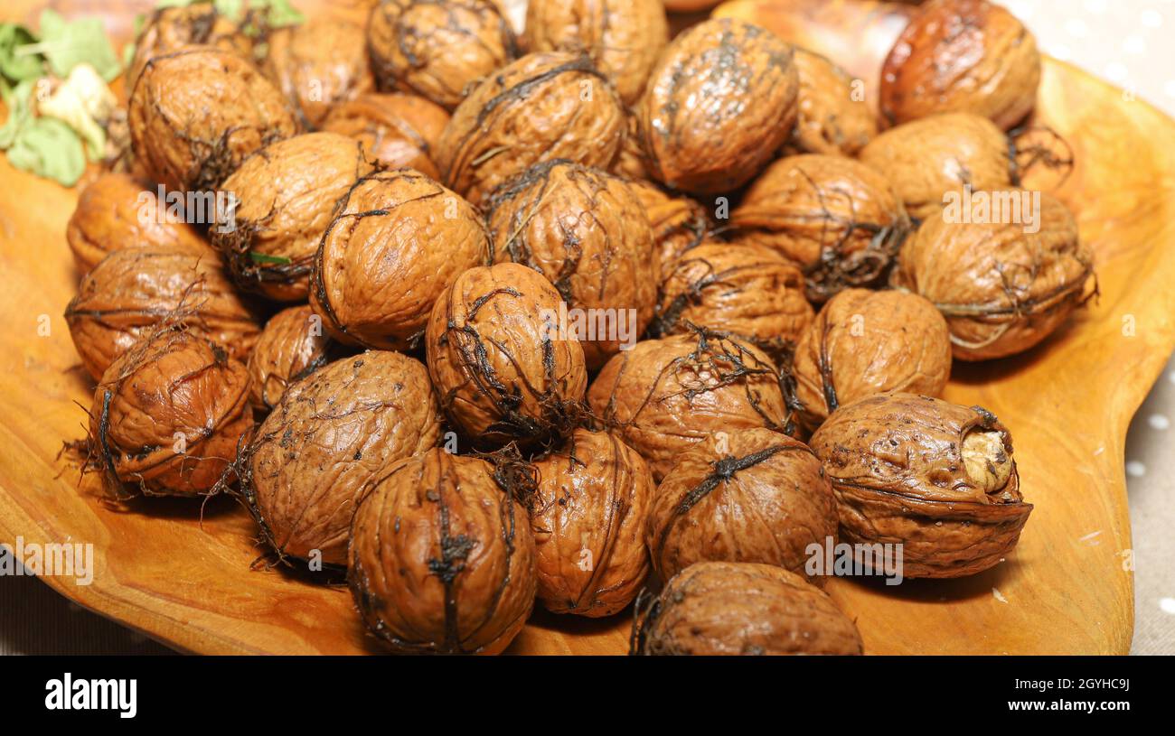 Fresh harvest walnuts with shells and water drops in wooden bowl ...