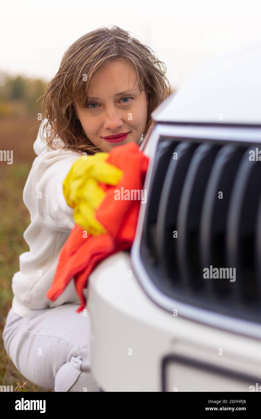 A pretty young woman in a white hoodie and yellow rubber gloves wipes ...