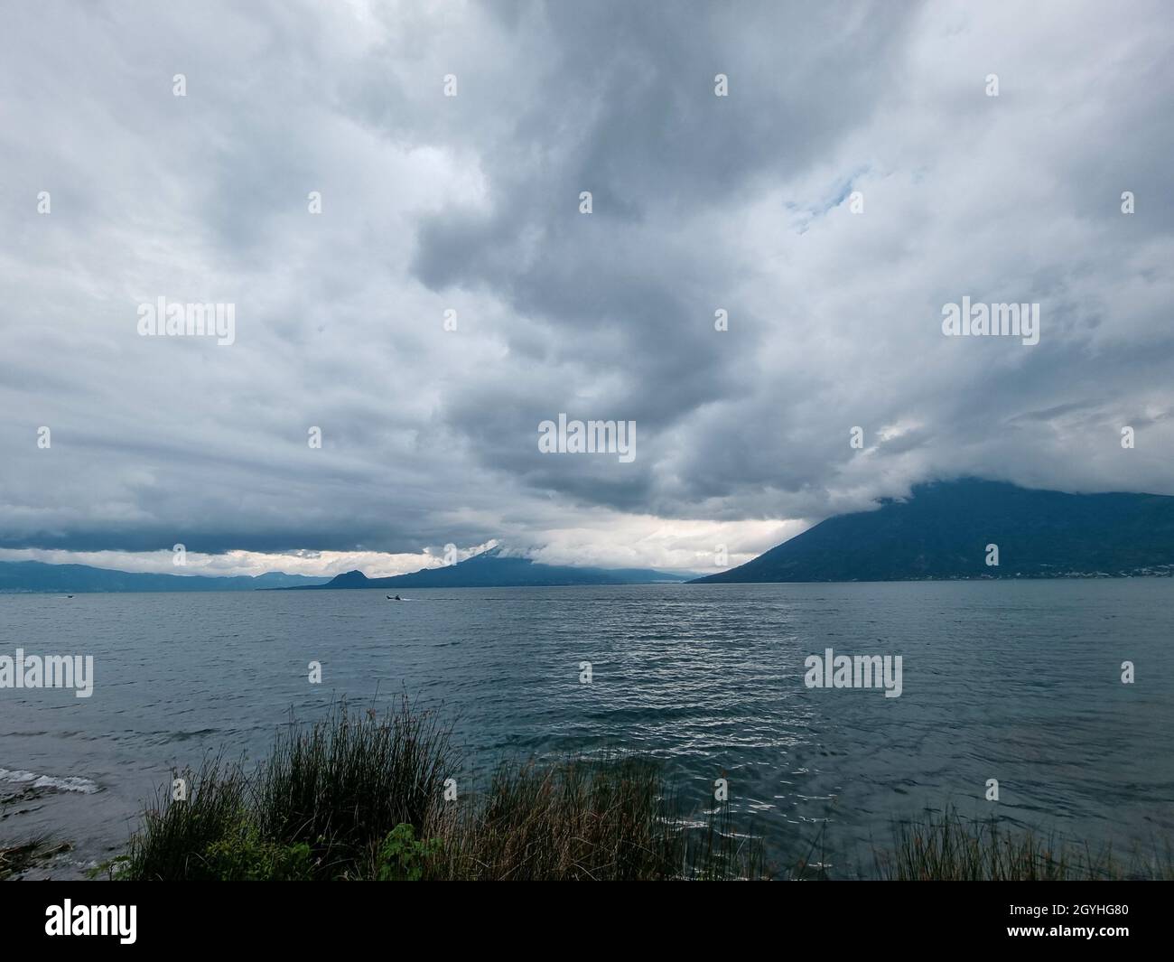 Eerie landscape of the Lake Atitlan under heavy gray clouds in ...