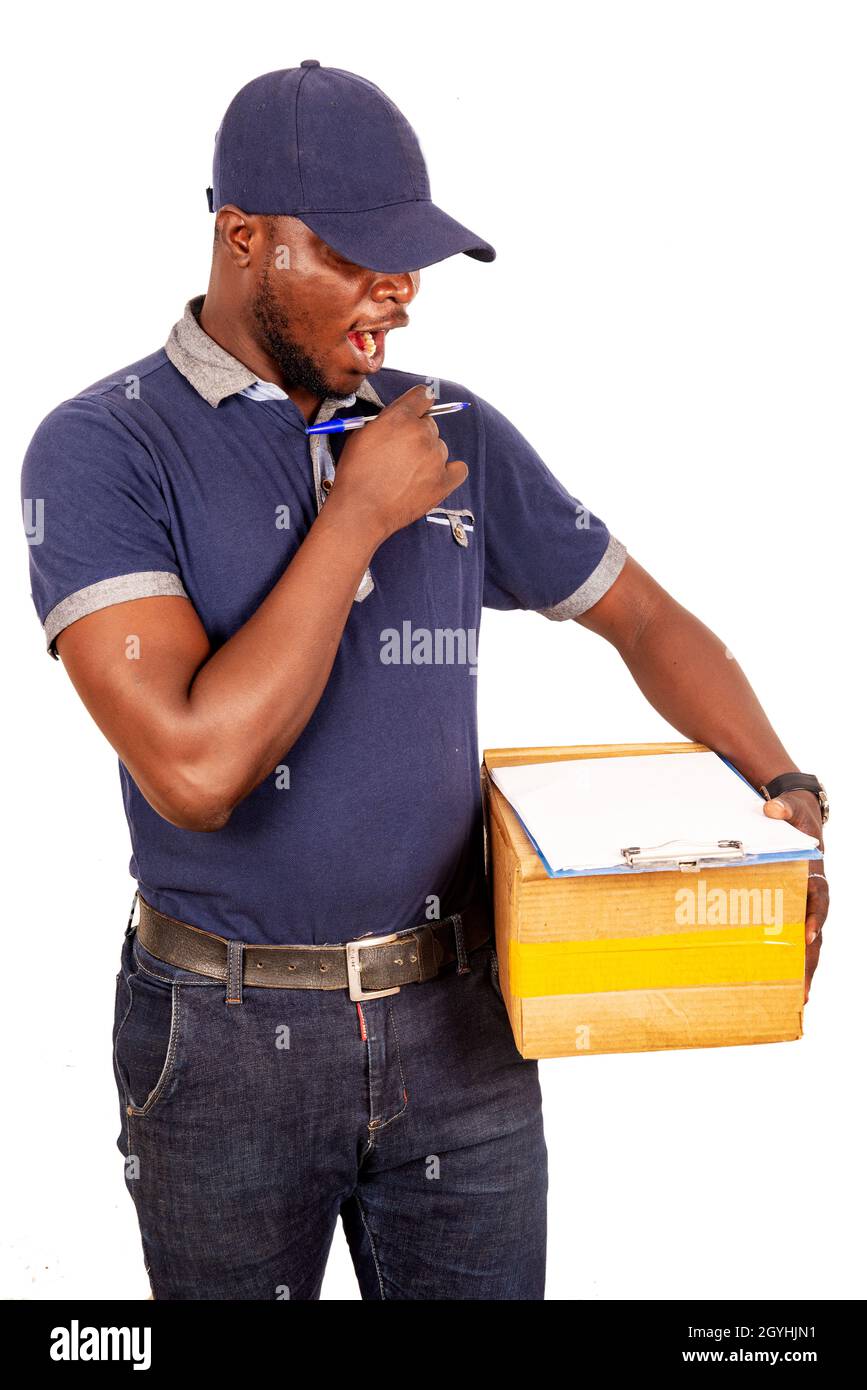 a delivery man standing in cap on white background looking at cardboard ...