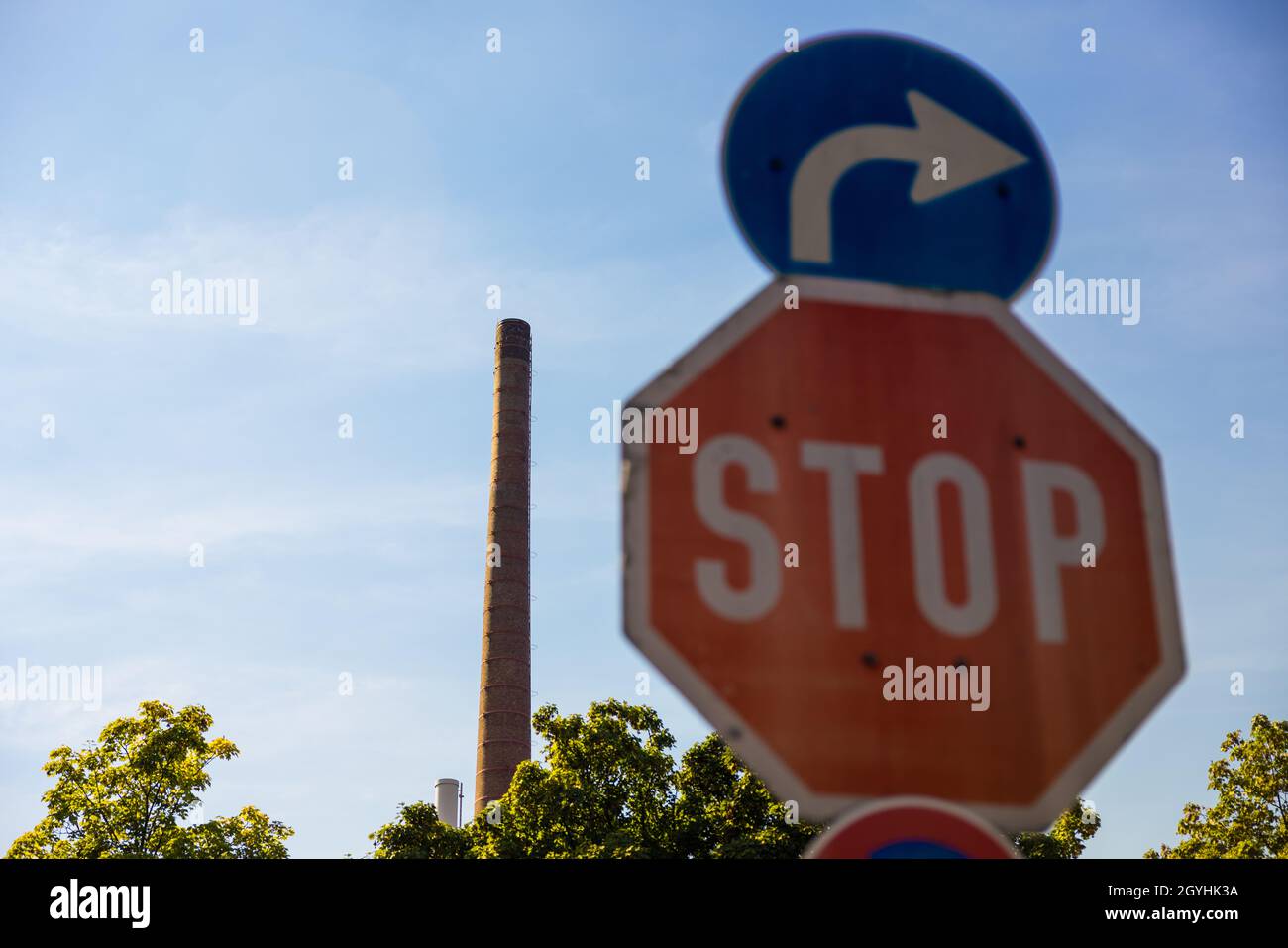 Stop sign and turn sign with a factory chimney in the background Stock ...