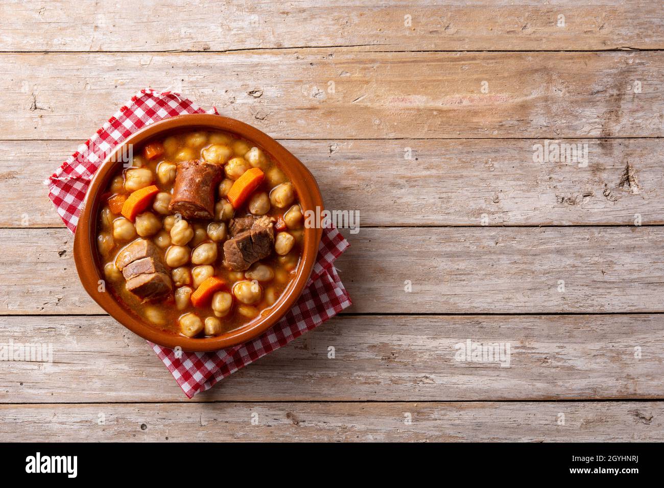 Traditional Spanish cocido madrileño in bowl on rustic wooden table ...