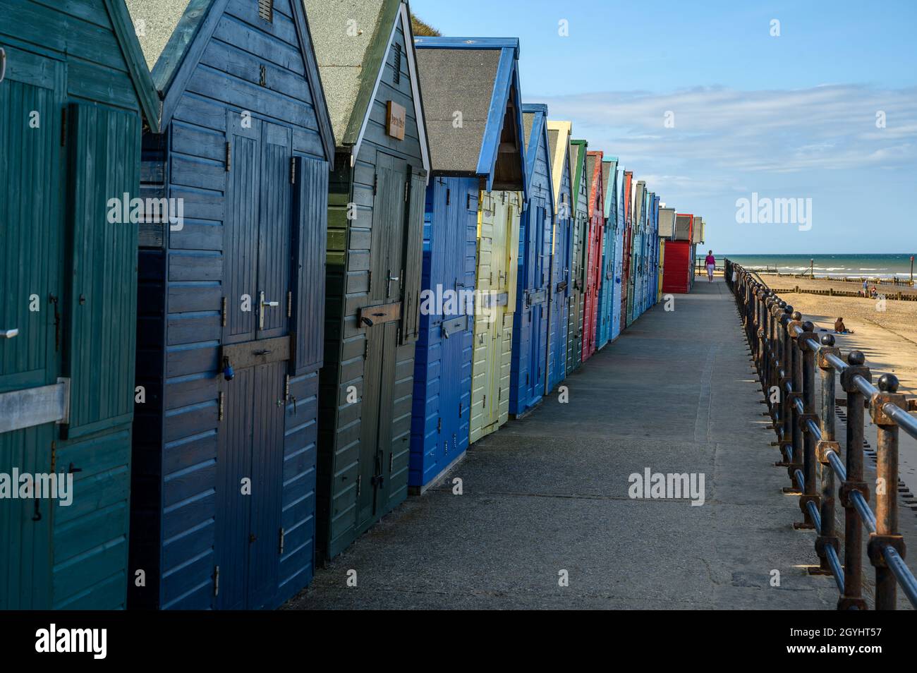 A row of brightly coloured, painted beach huts on Mundesley beach ...