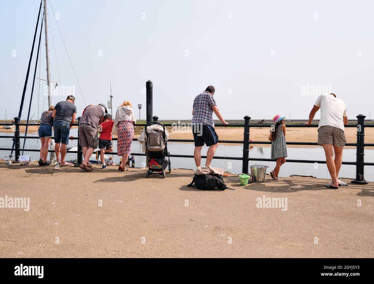 Summer seaside family tourists crabbing along the quayside in Wells ...