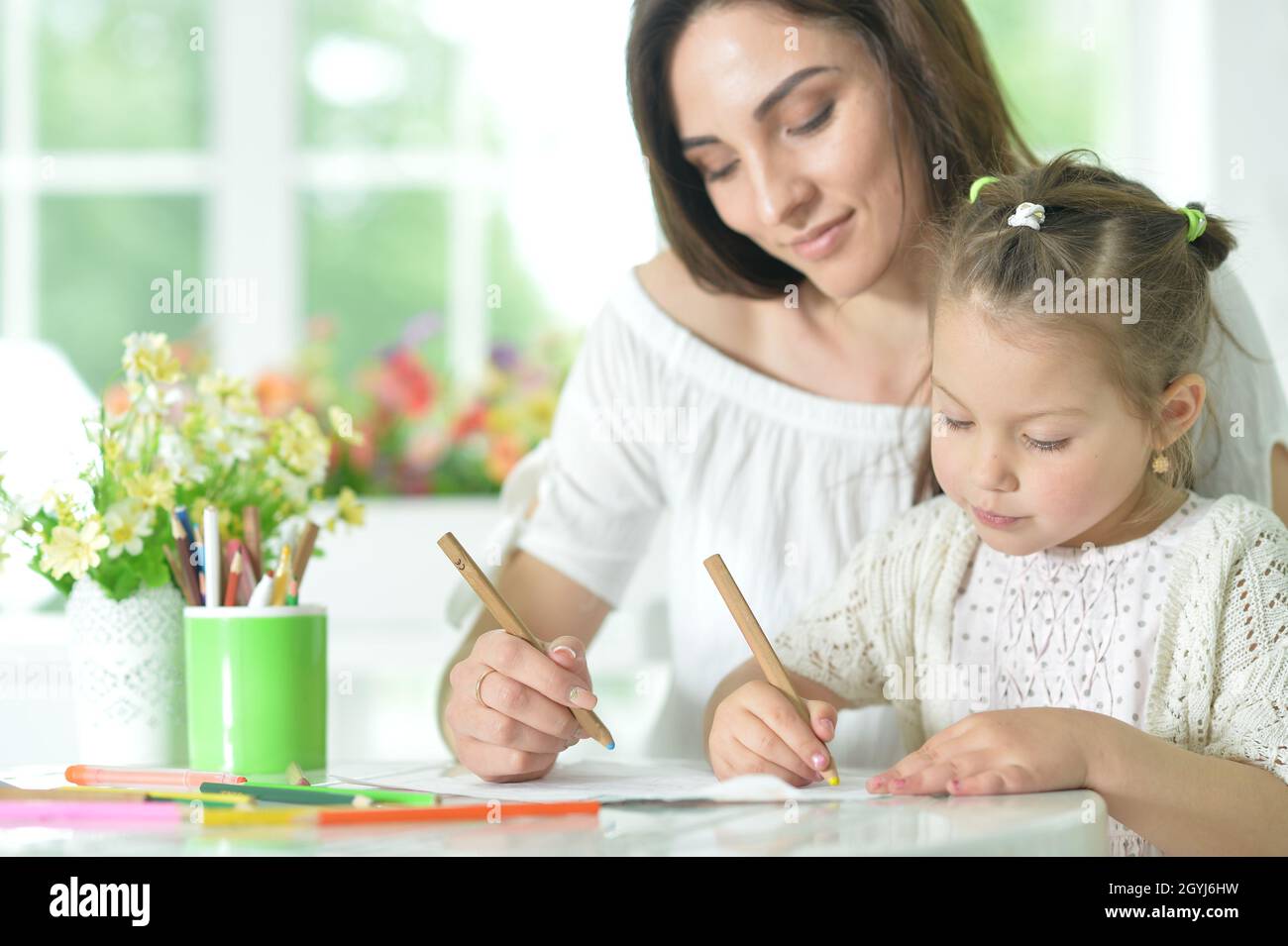 Cute girl with mother drawing at the table Stock Photo - Alamy