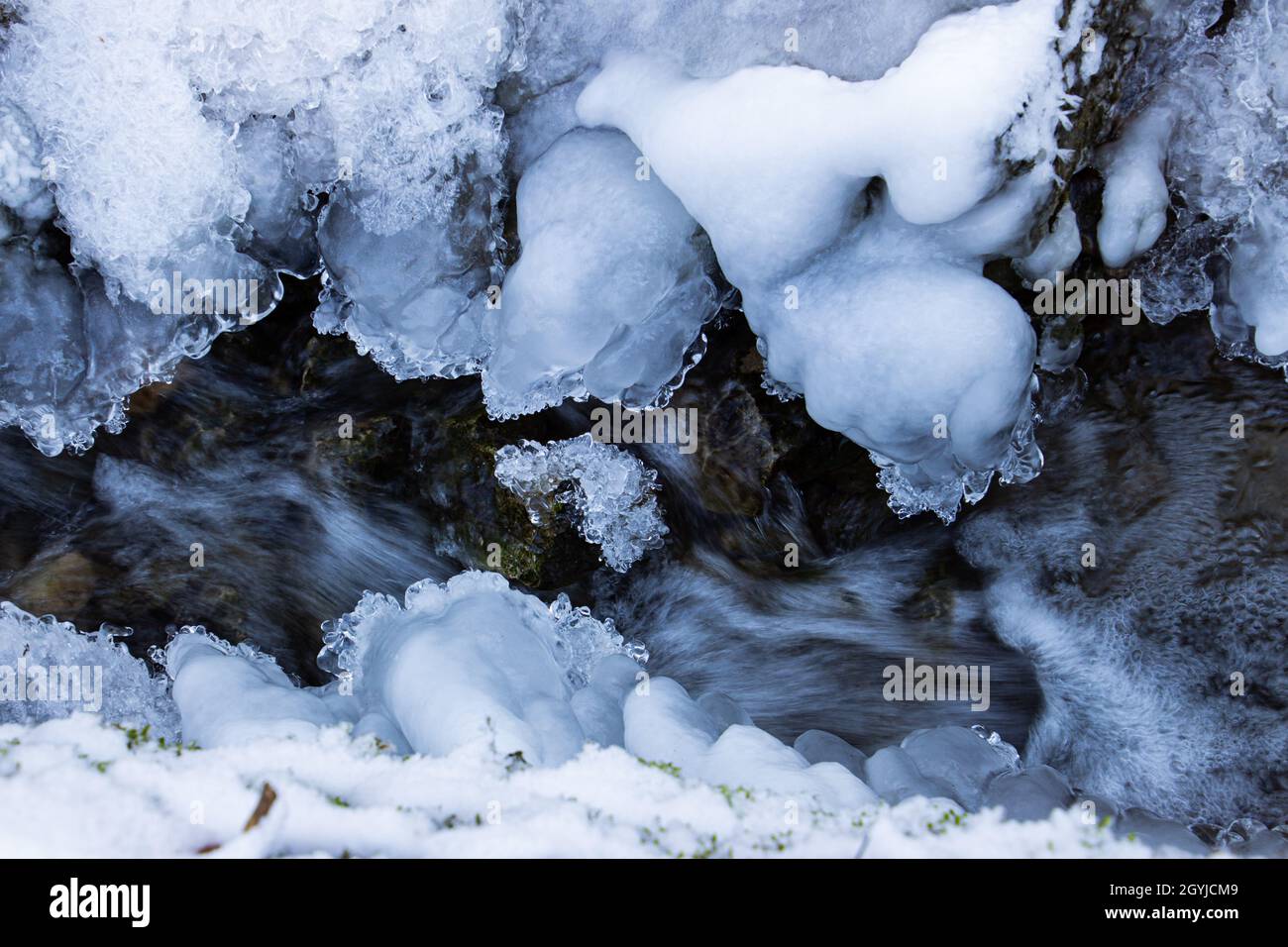 Small waterfall in a forest creek with frozen rocks and icicles Stock ...