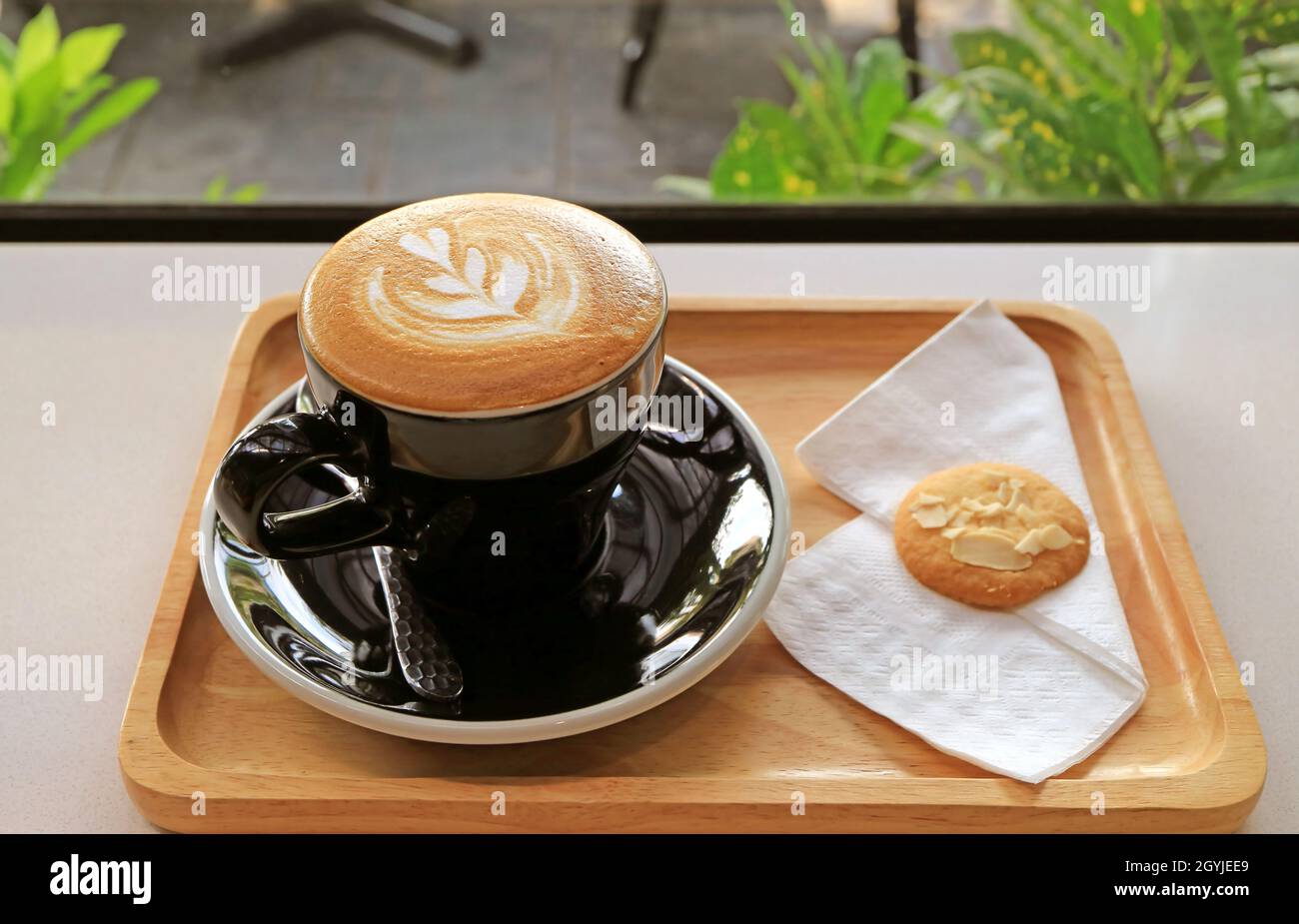 Cup of delectable cappuccino coffee with a butter cookie on windowside ...