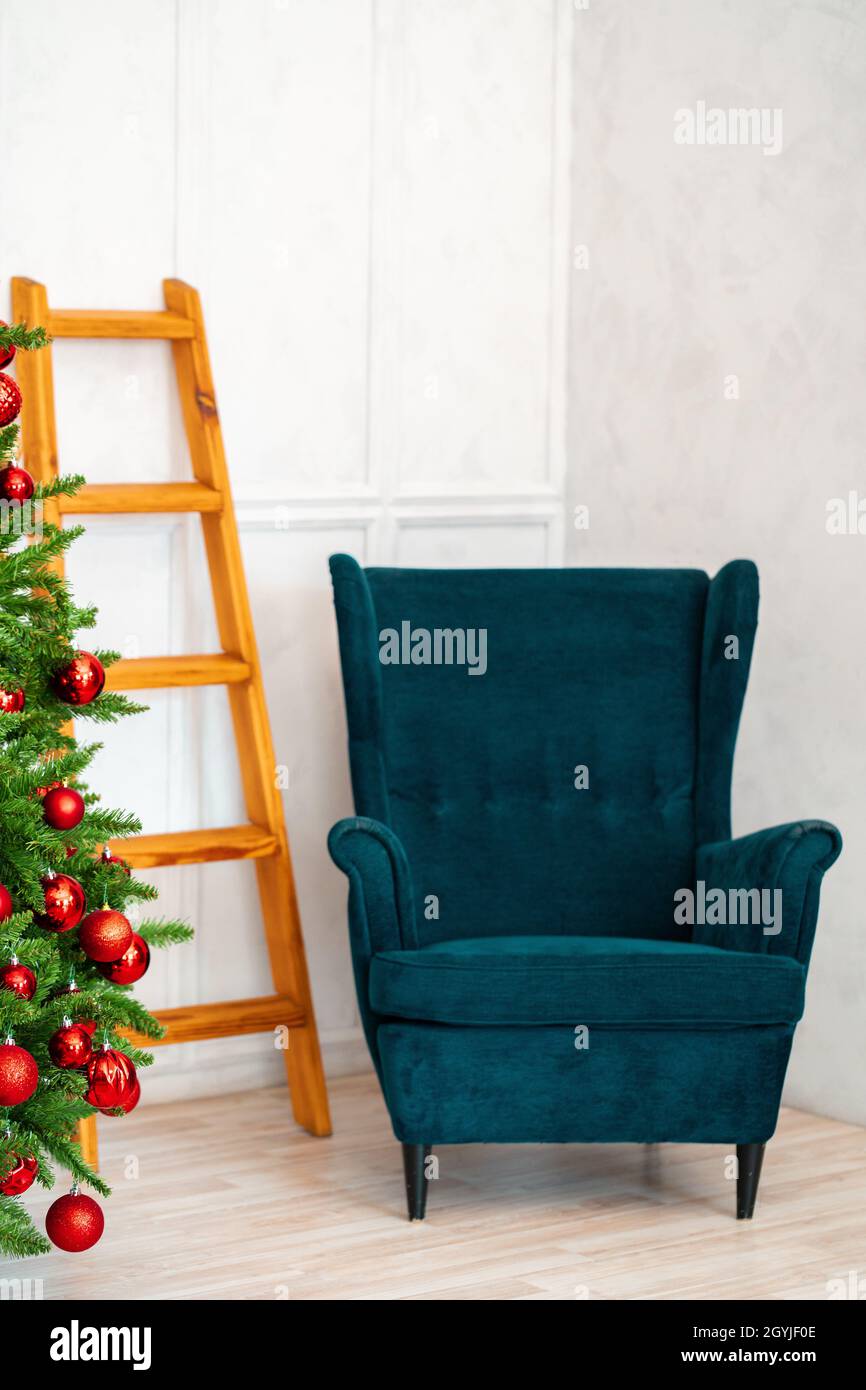Holiday interior. Beautiful decorated christmas tree with blue armchair ...