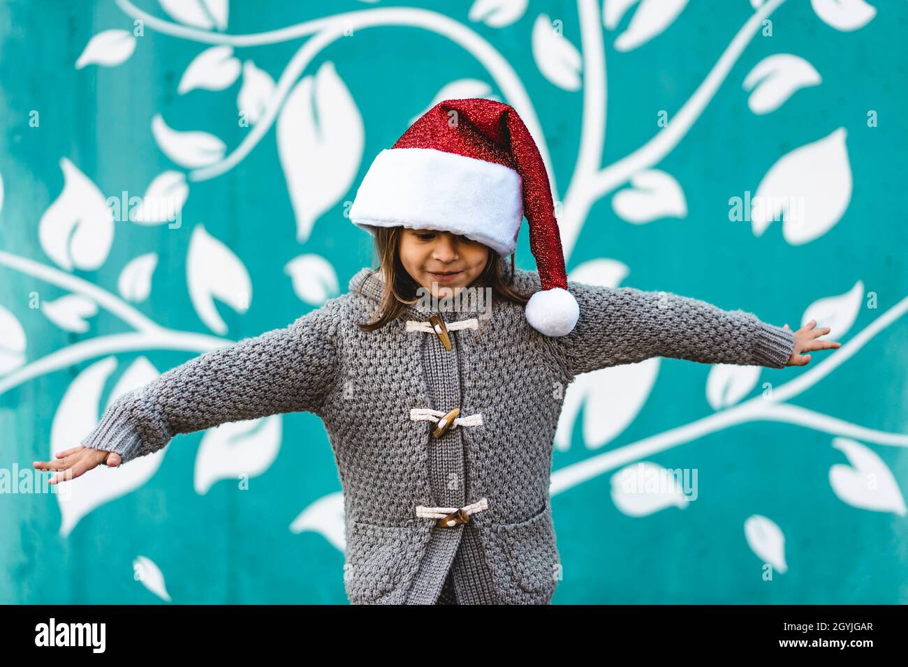 Little girl wearing santa claus hat flying with open arms like a plane ...