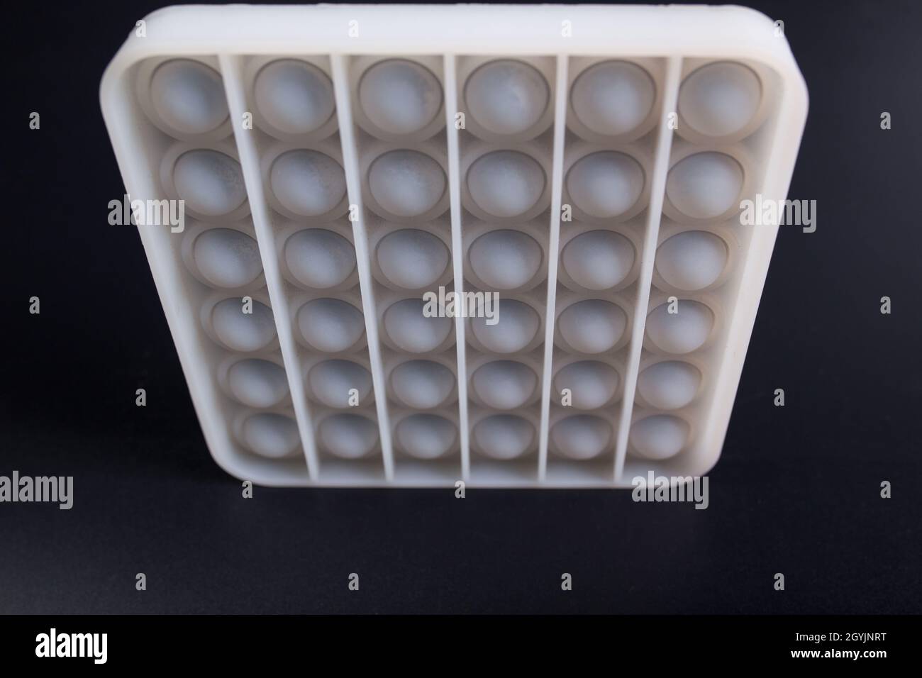 White pop it antistress toy close up, on black background Stock Photo ...