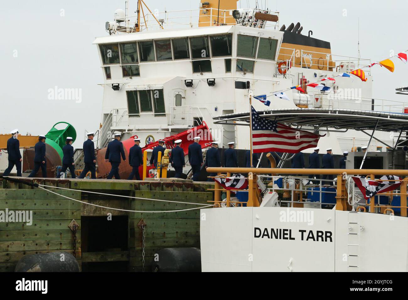 Crew members of the Coast Guard Cutter Daniel Tarr walk toward the vessel to perform a manning ...