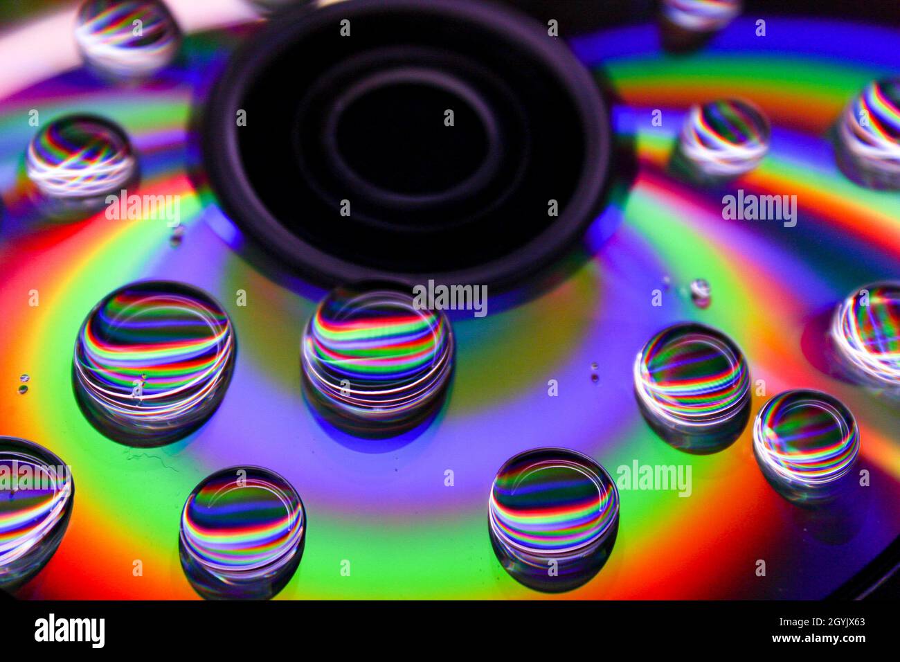 Closeup of a compact disc with rainbow color reflection and water drops ...